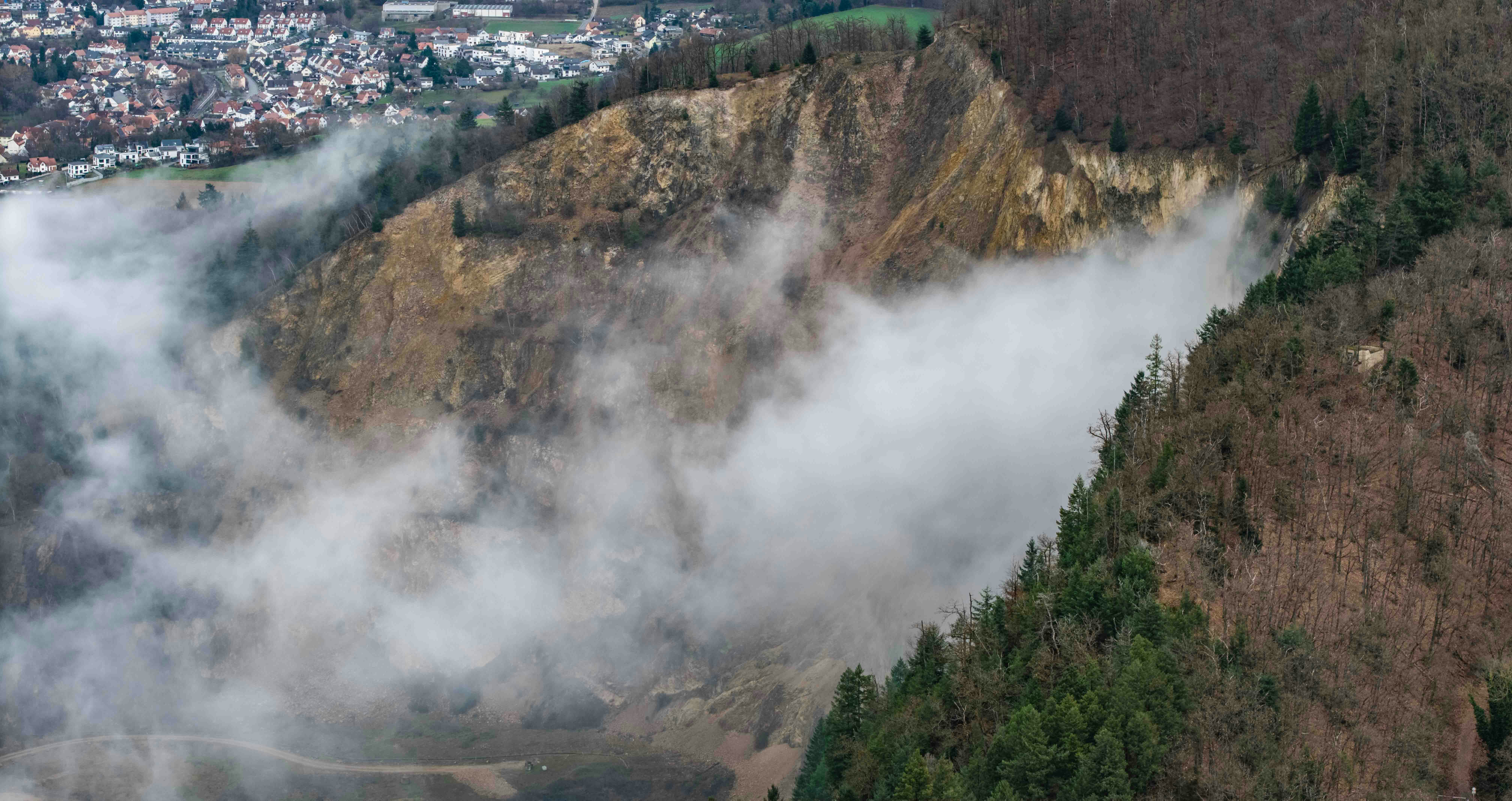 Mist threading the cliffed gorge under a hillside forest