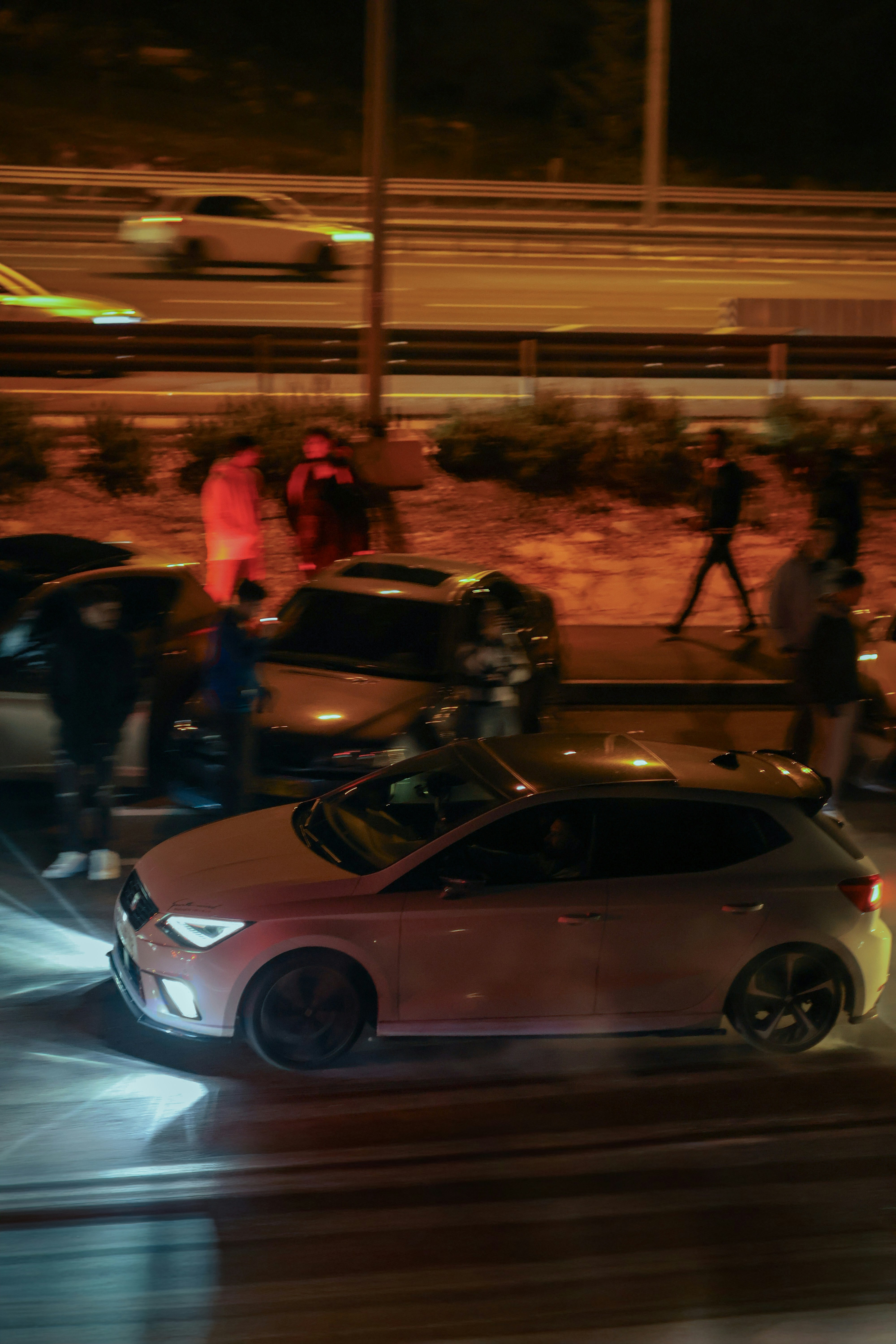 Neon Night Car Meet: A Silver Hatchback Hums in Streetlight Glow