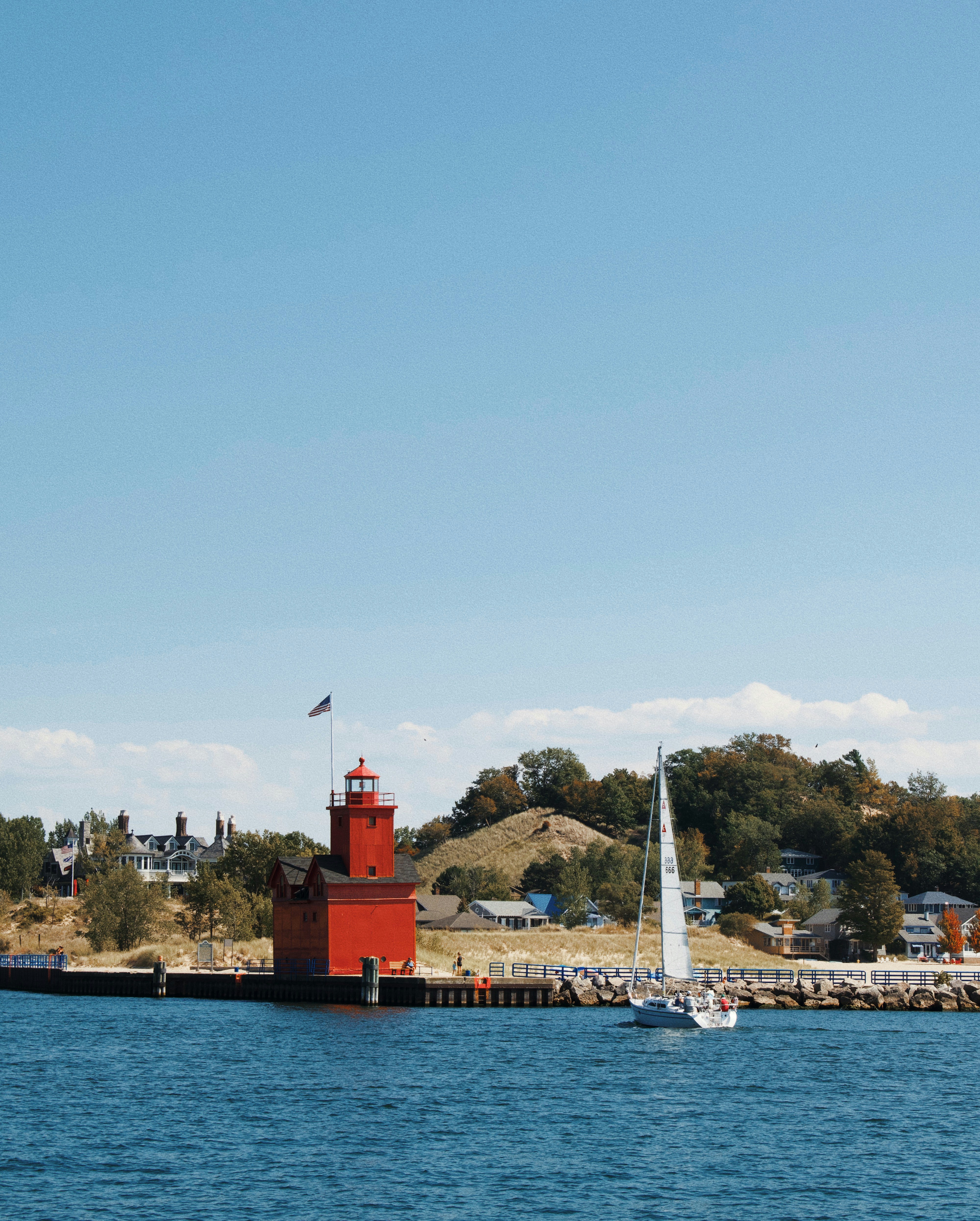 Red Lighthouse and Sailboat at Daybreak Harbor