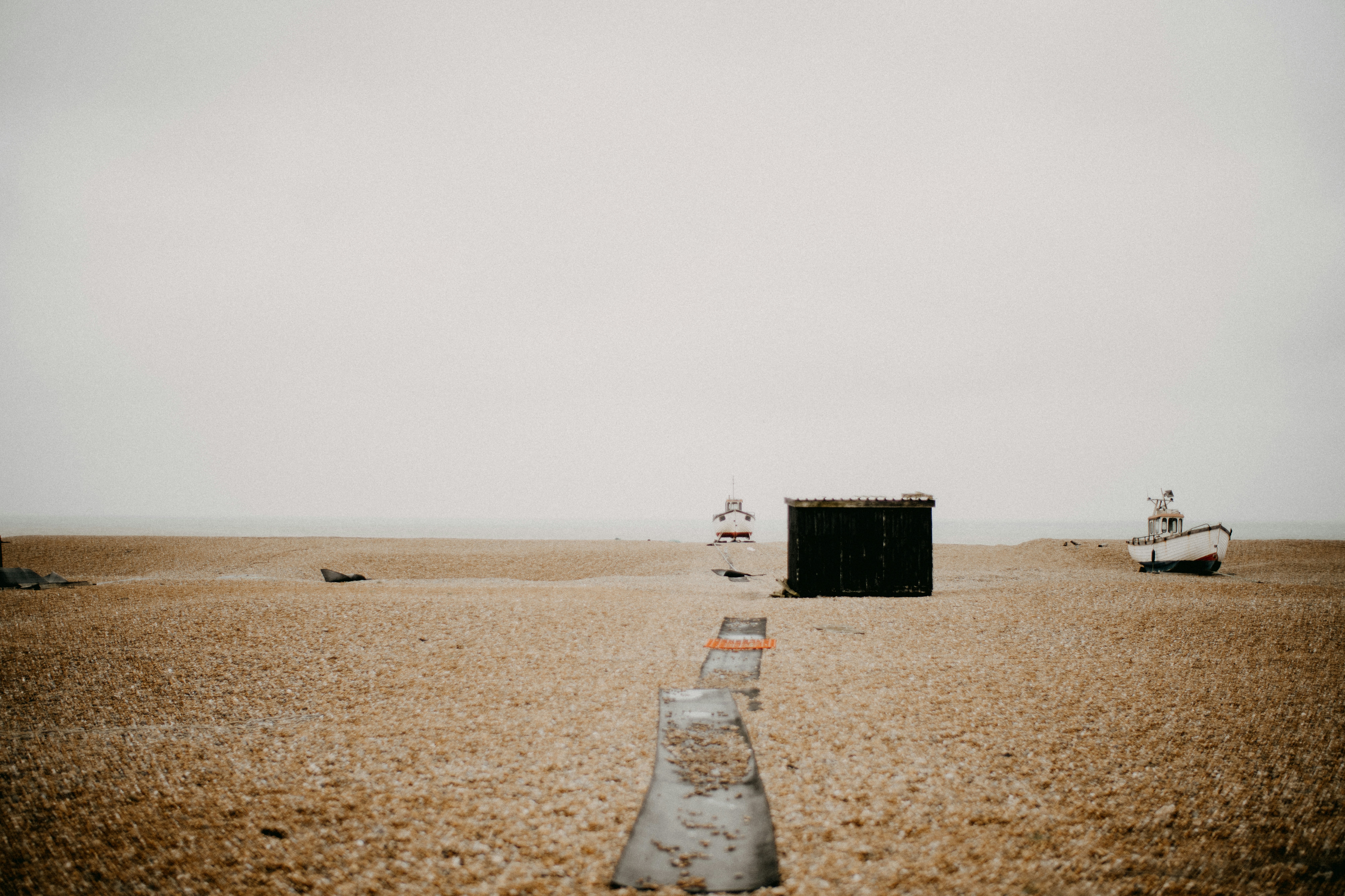 Minimal Pier Lure: A Pebbled Horizon with a Distant Shoreline