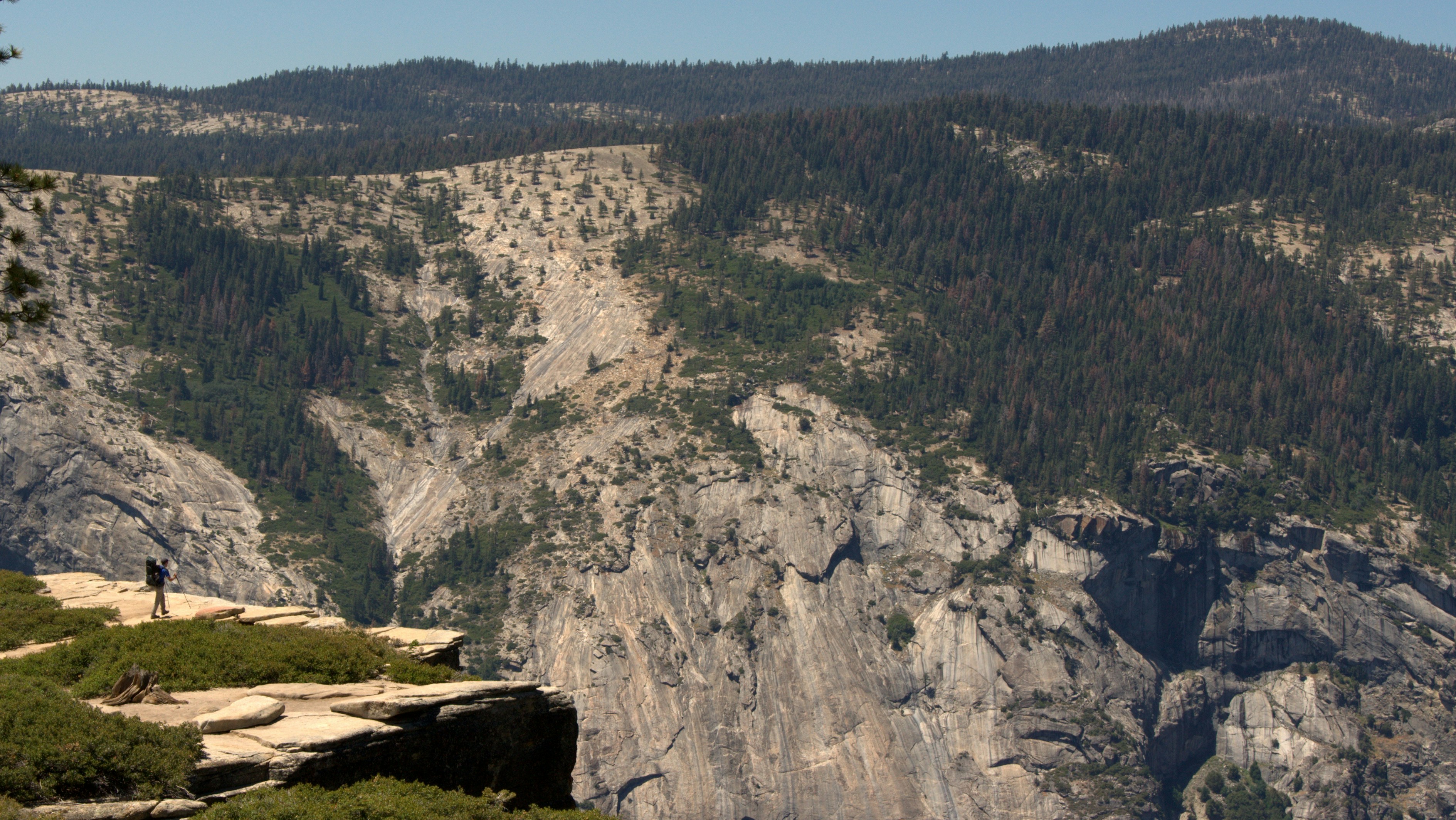 Person standing on a cliff overlooking a valley.