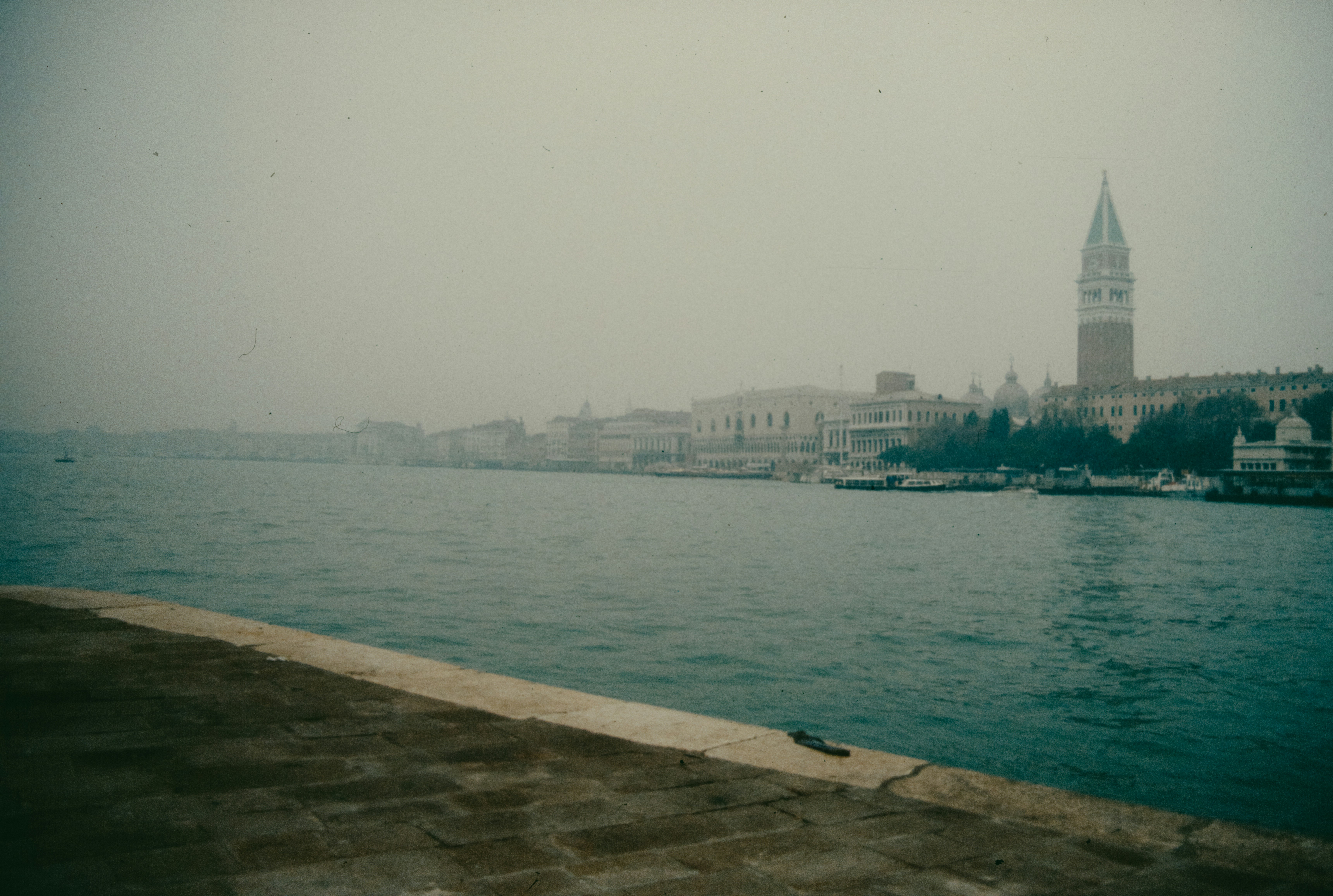 Foggy view of venice cityscape with canal and tower.