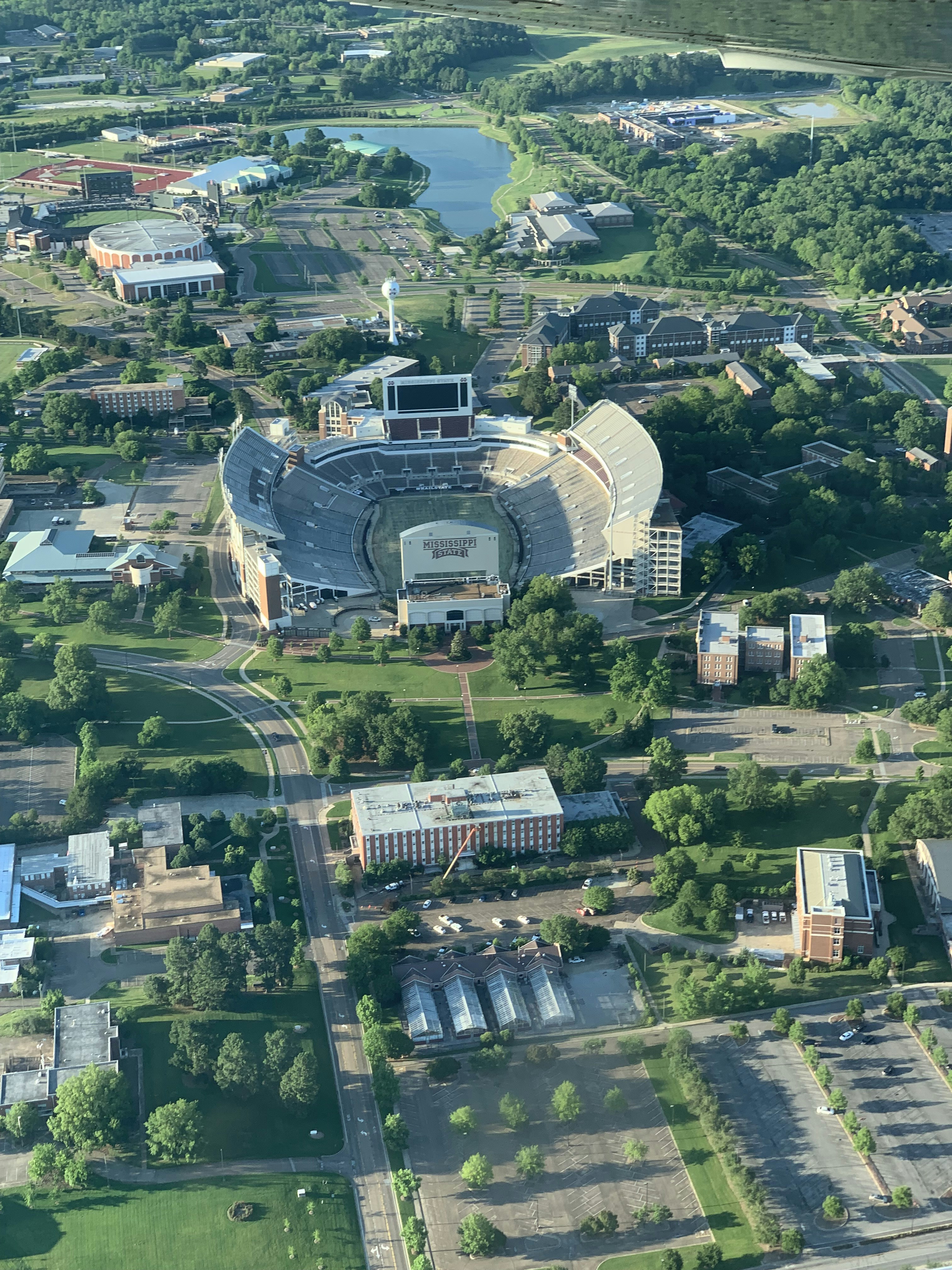Shot from a small airplane, this aerial view highlights a college football stadium surrounded by campus and city landscape.