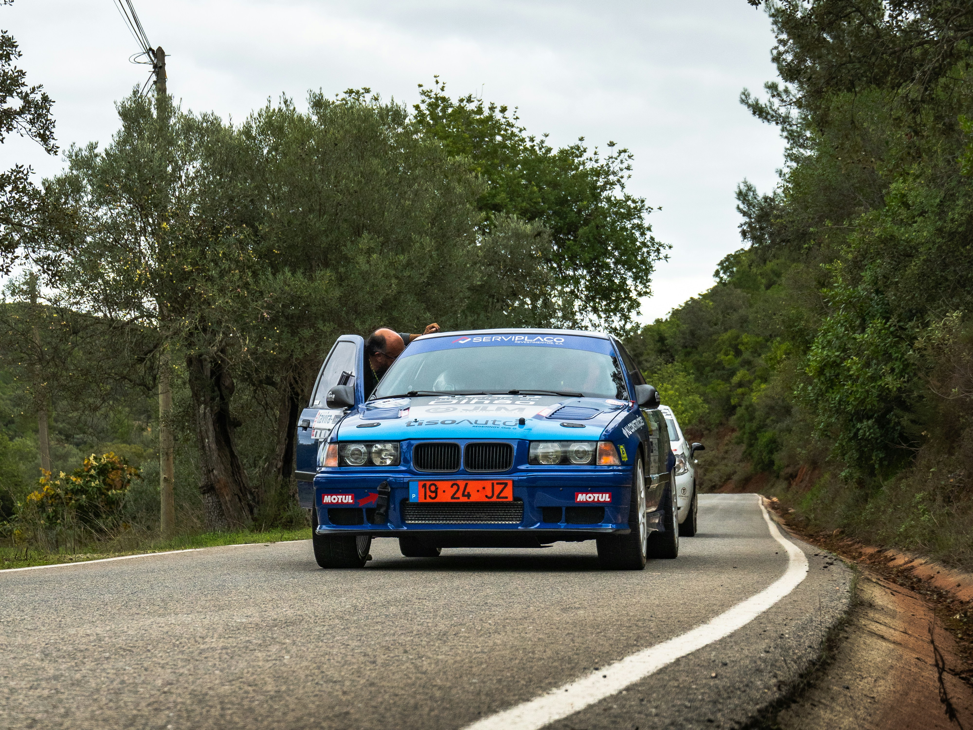 Blue rally car paused on a winding country road