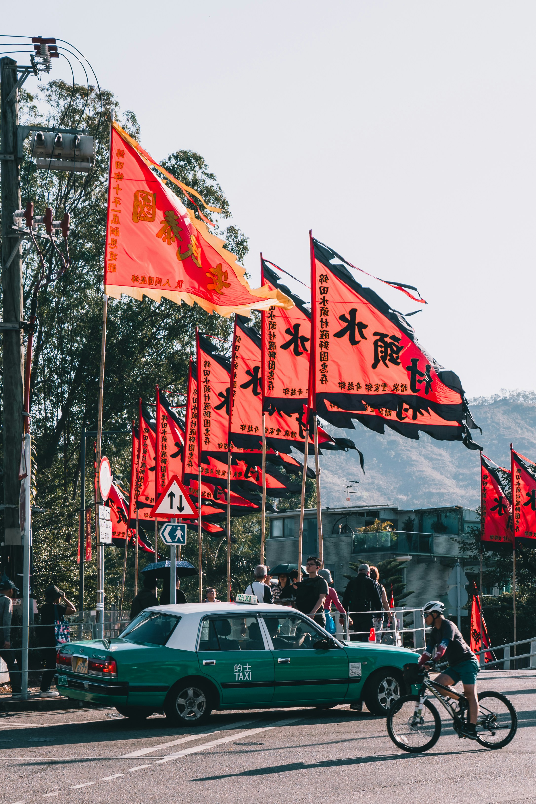 Red Flags and City Pace: A Street Scene Framed by Moving Taxis