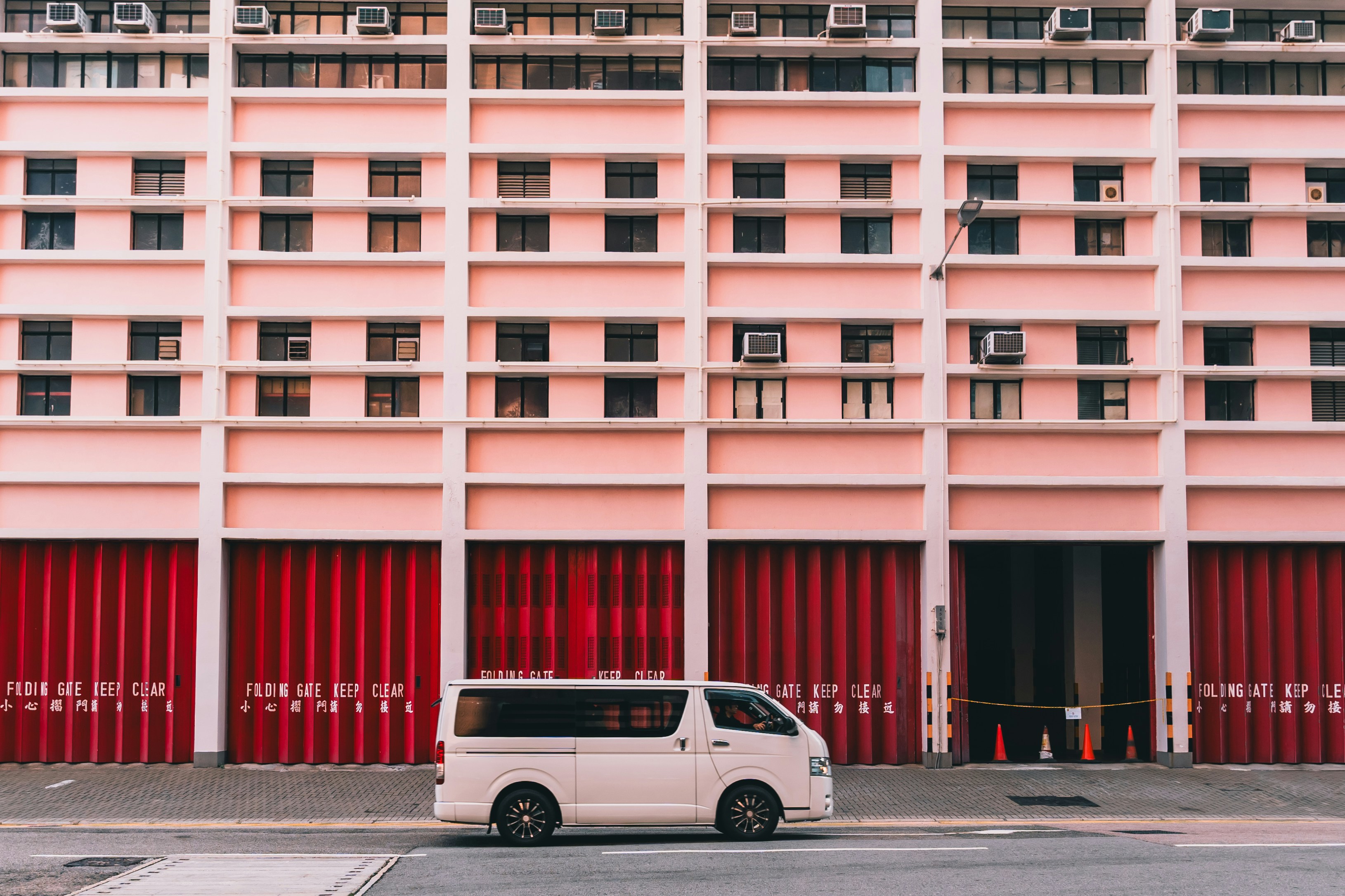 White van beneath a terraced pink facade