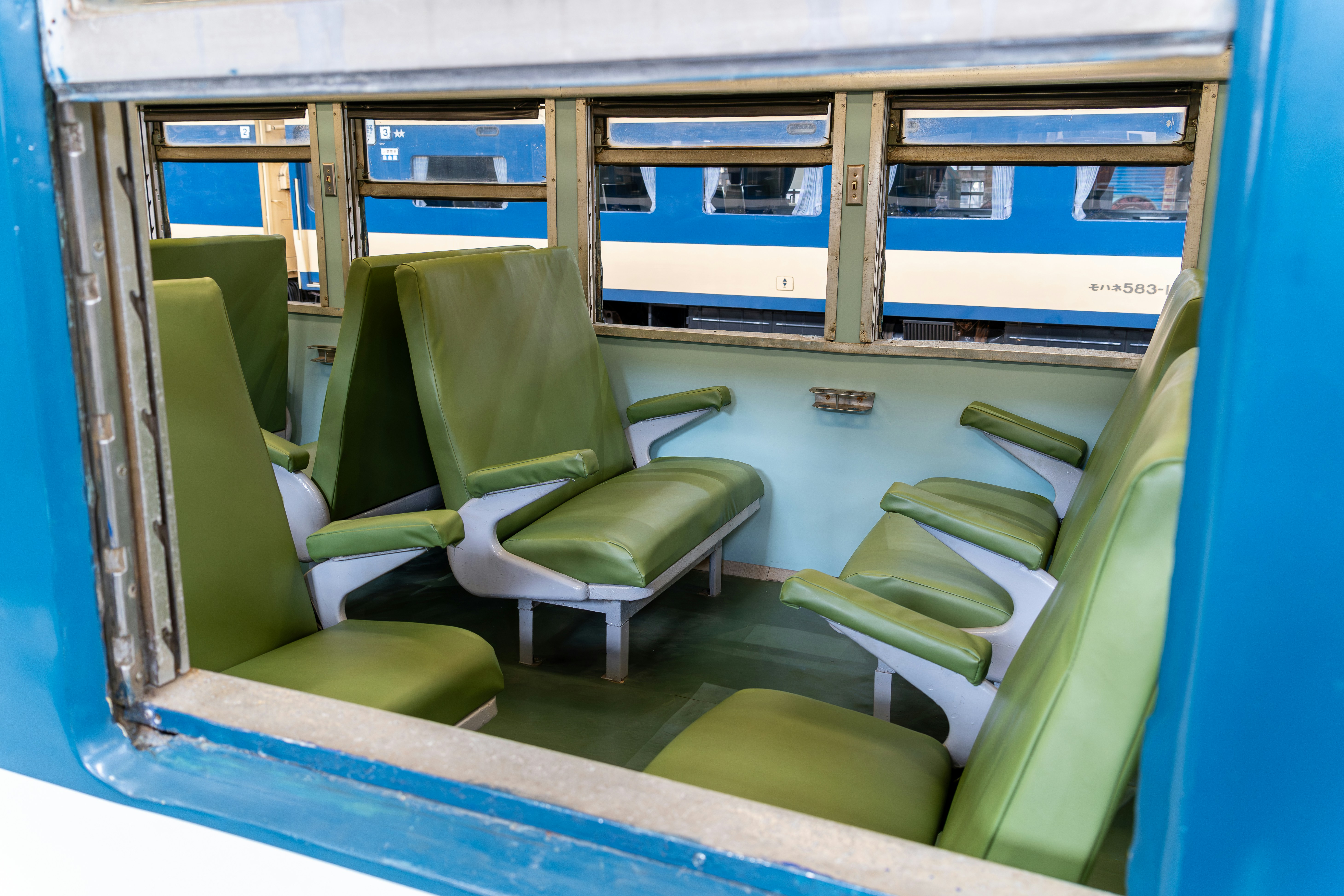 Vacant Carriage: Olive Seats Quietly Beneath Blue Window Frames