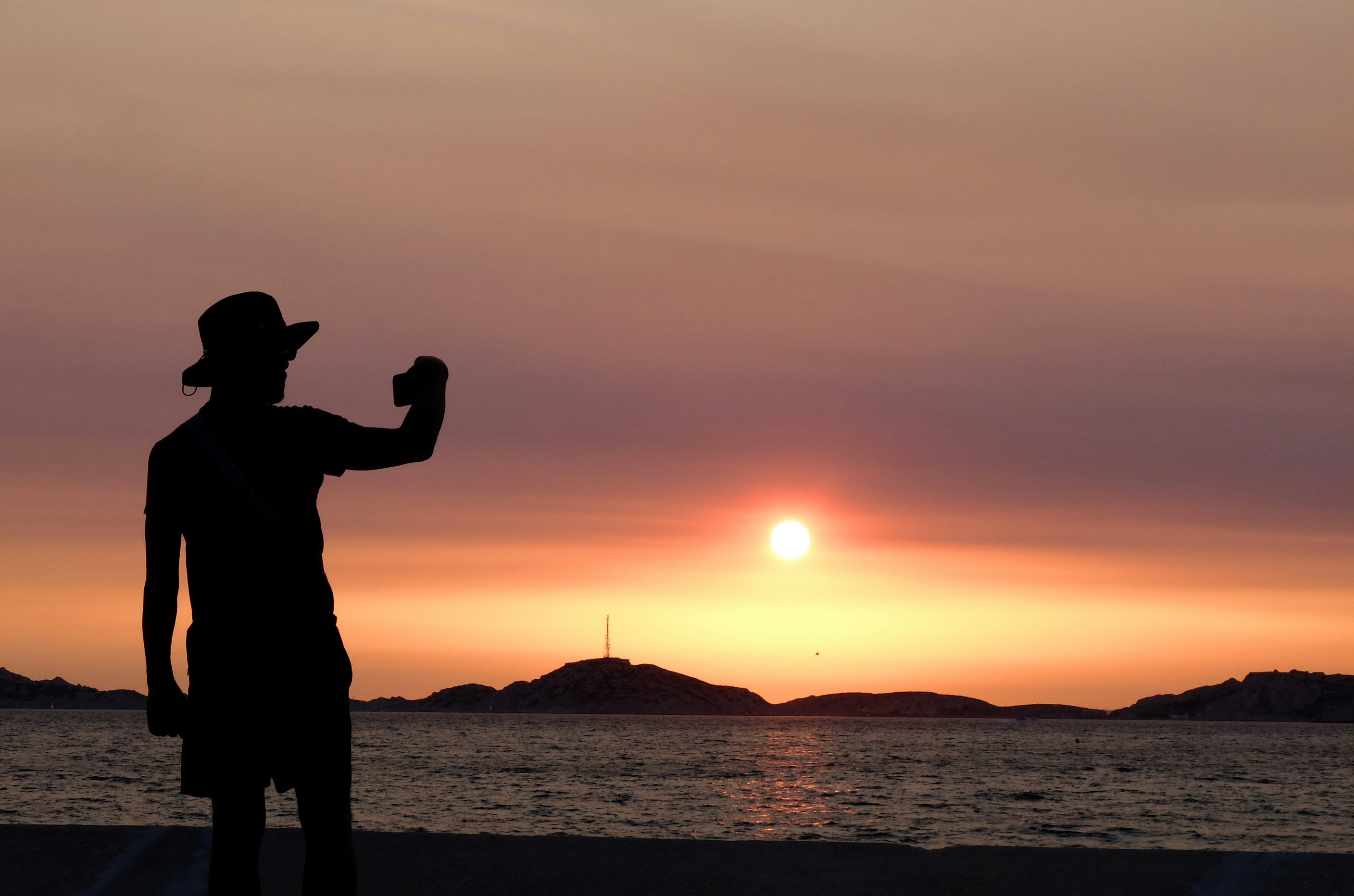 Sunset Silhouette: A Lone Figure Holds the Moment by the Sea