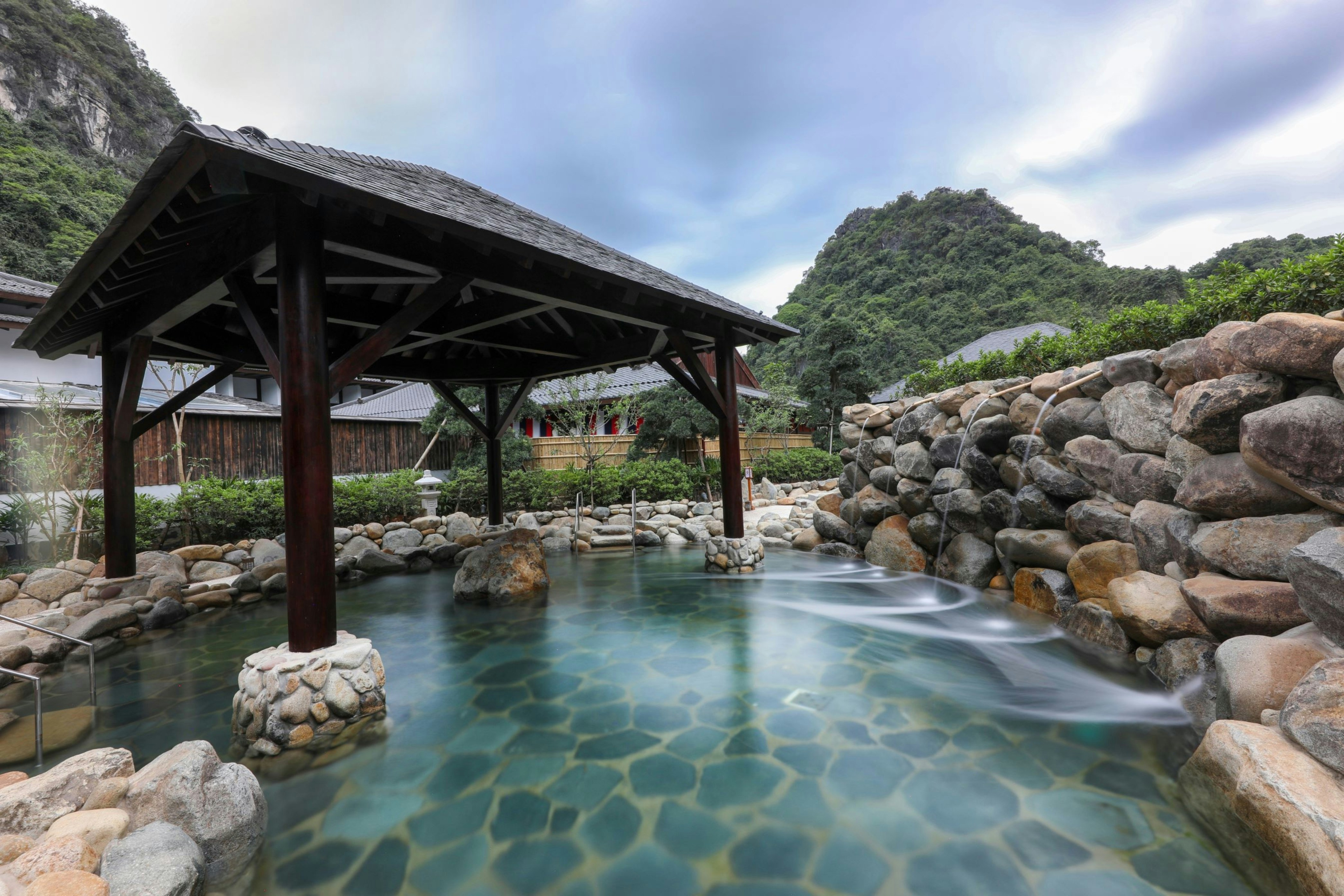 Outdoor hot spring pool with rocky waterfall and pavilion. photo – Free ...