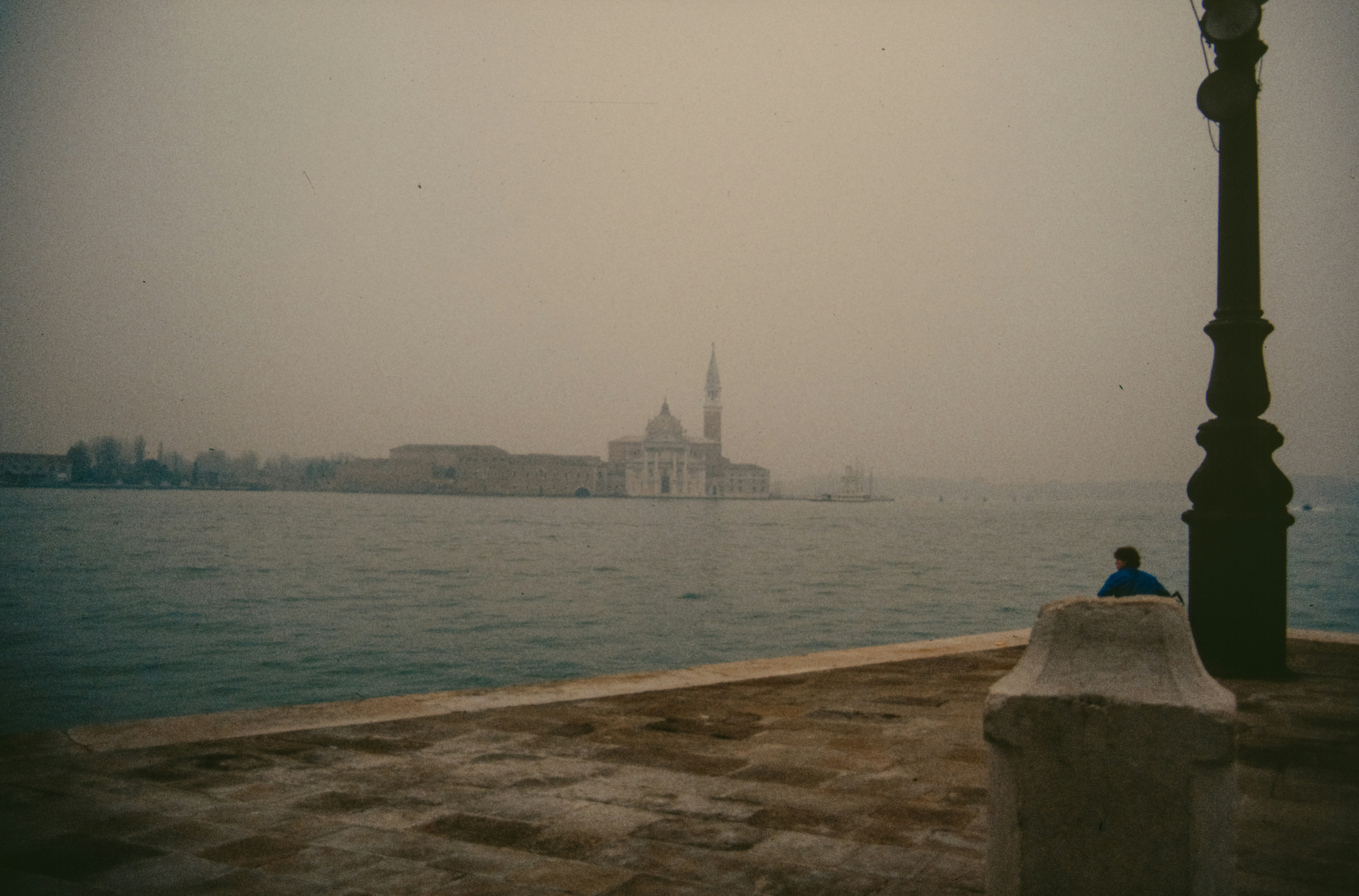 Harbor Silhouette: A Quiet Seaside Moment with a Lone Seated Figure