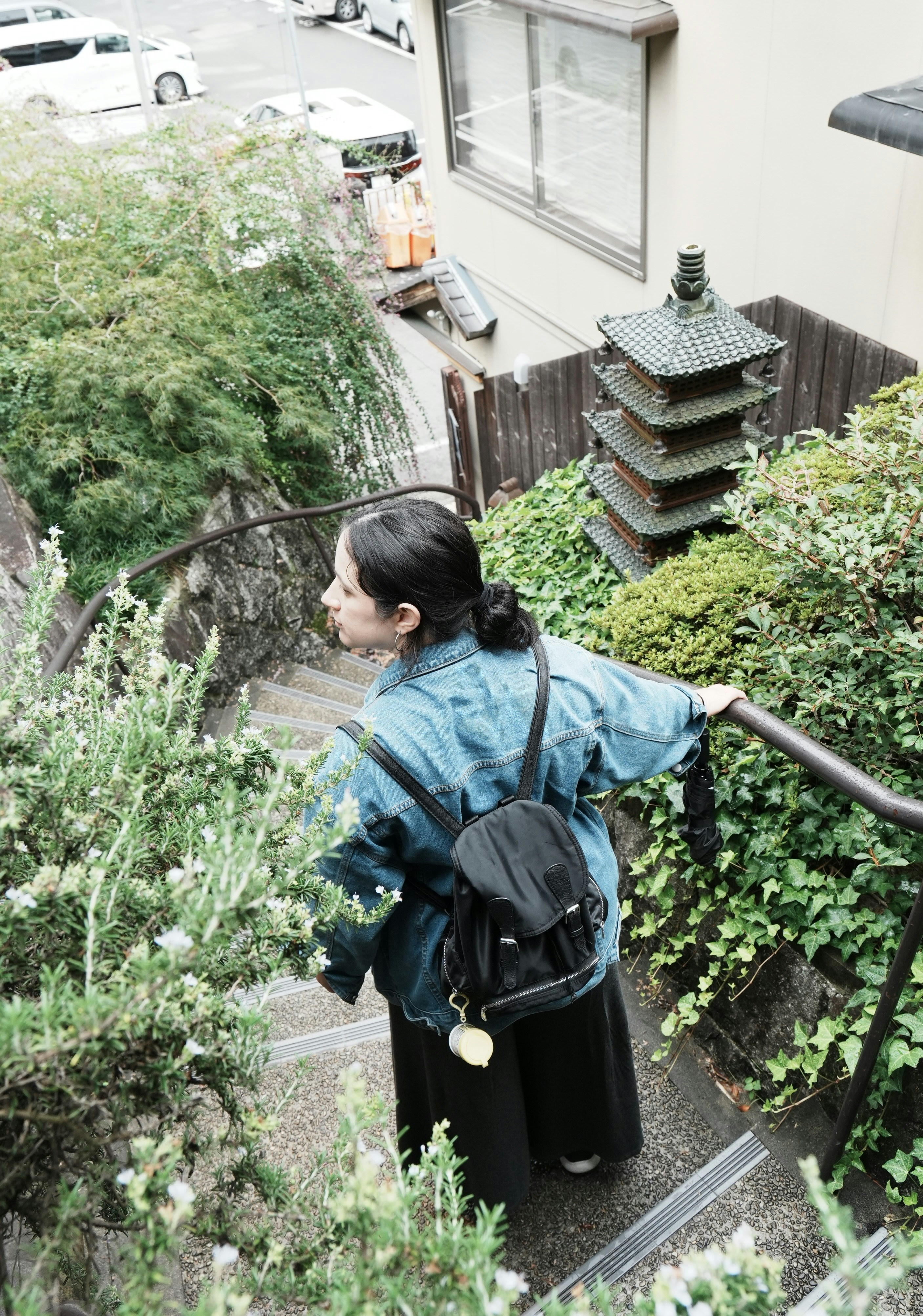 Urban Staircase Portrait: A Woman in Denim Descends Amid Garden Green