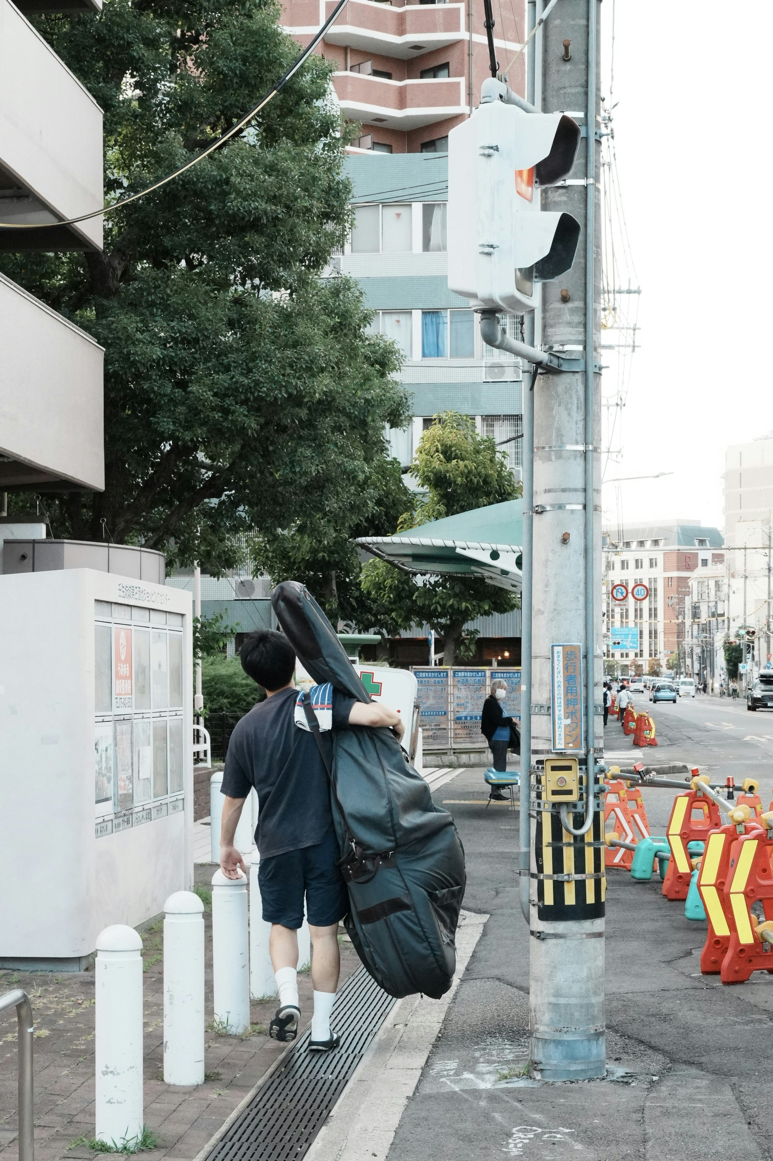 Two-Runed Path: Student Carries a Guitar Case Down a City Street