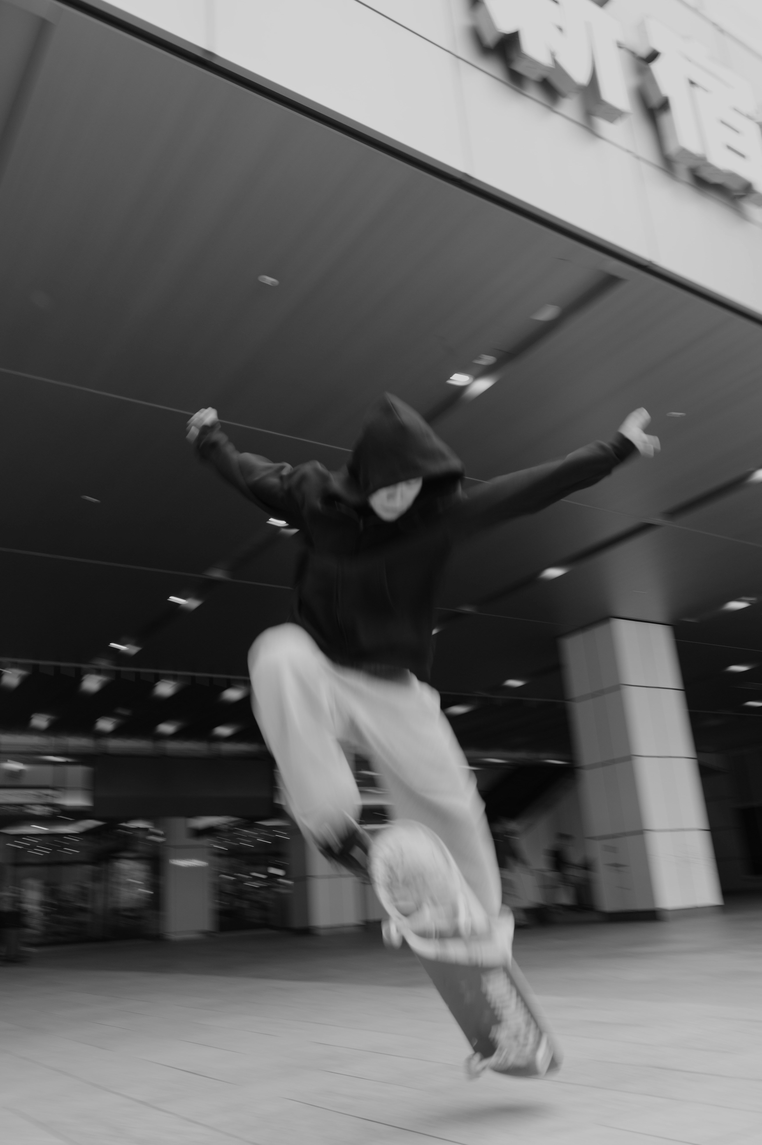 Midair Blur: A Hooded Skater Leaps Before a City Entrance