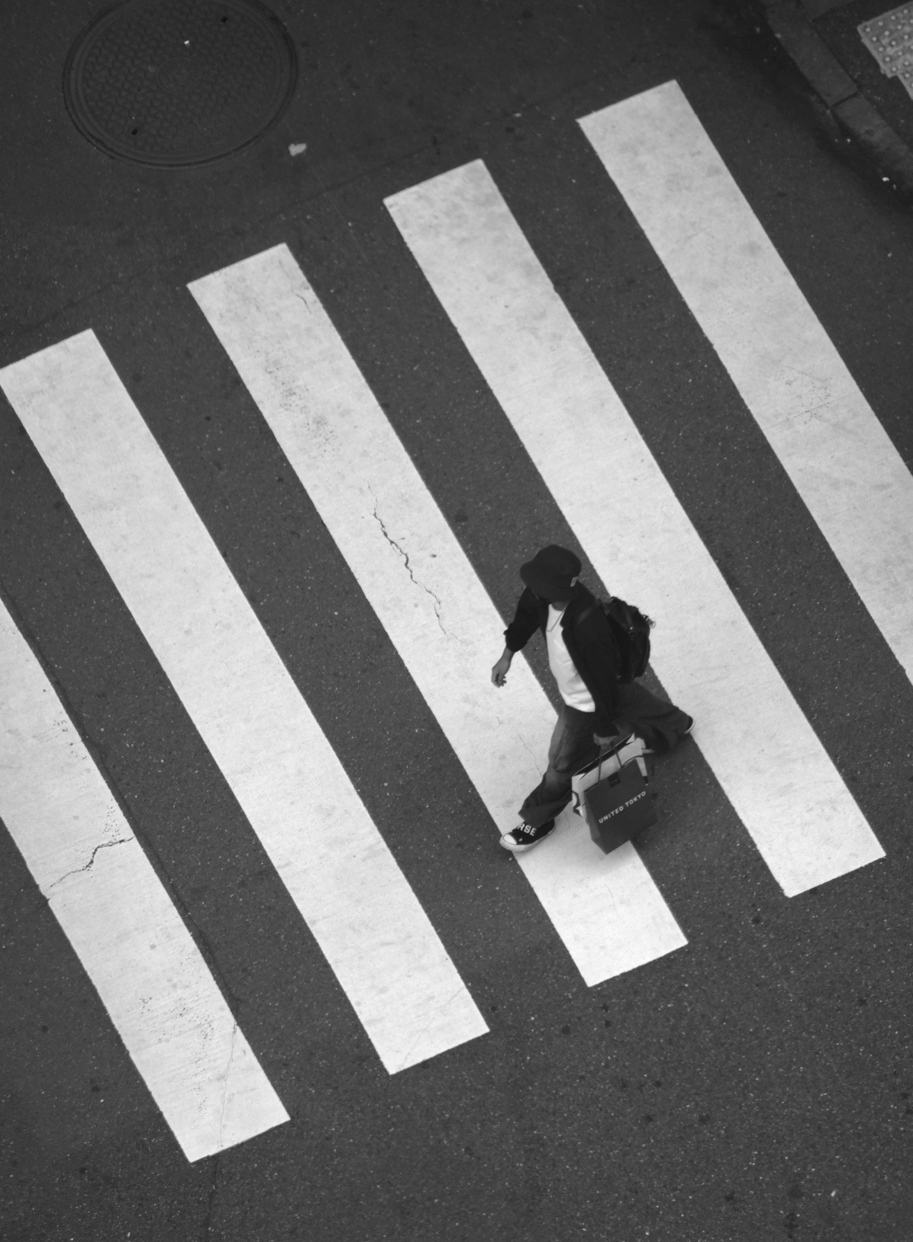 Person walking across a crosswalk with luggage photo – Free City Image ...