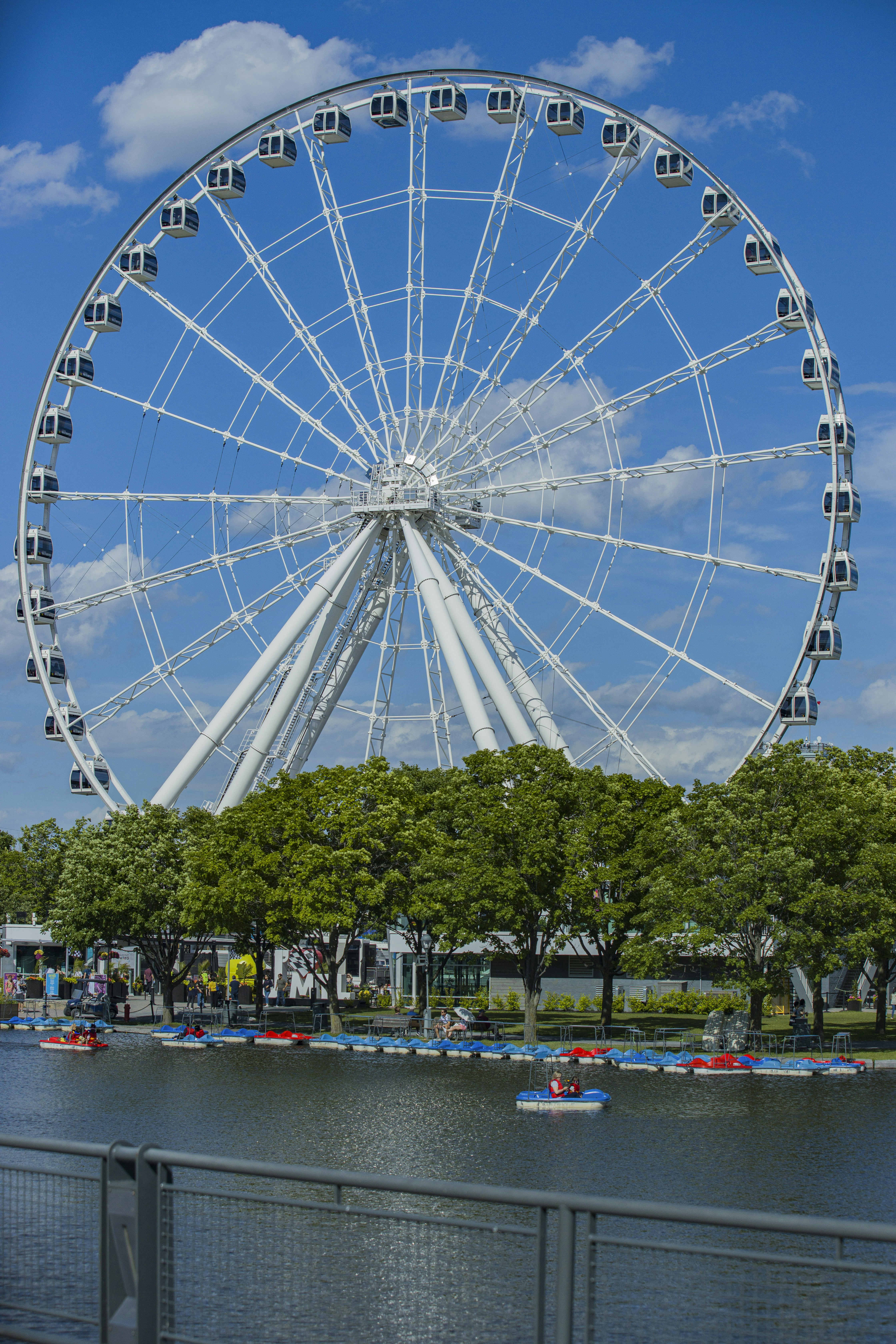 Giant Wheel Framed by Canal Boats and Green Canopy