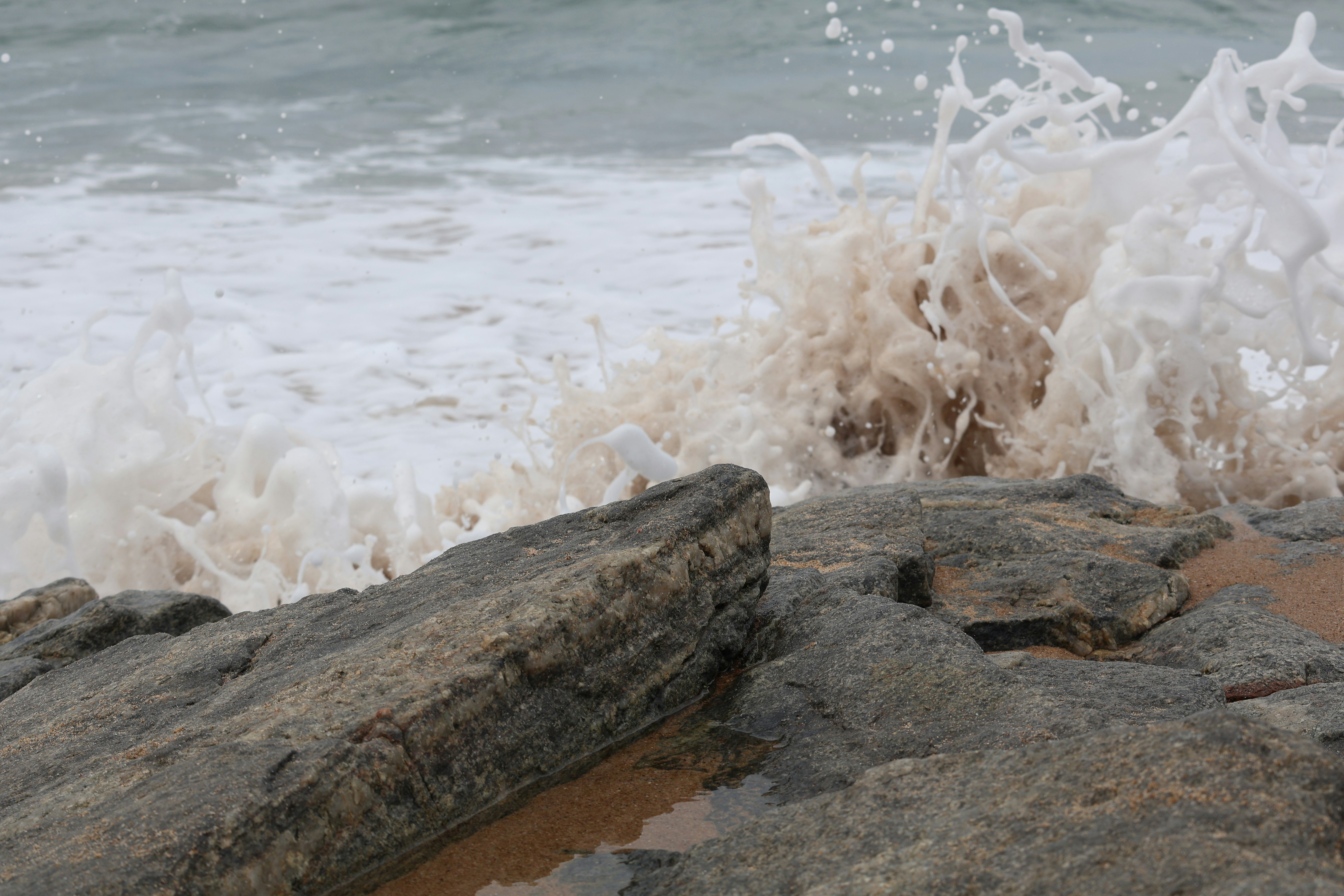 Wave Crash over Weathered Rocks: A Close-Up on Coastal Drama