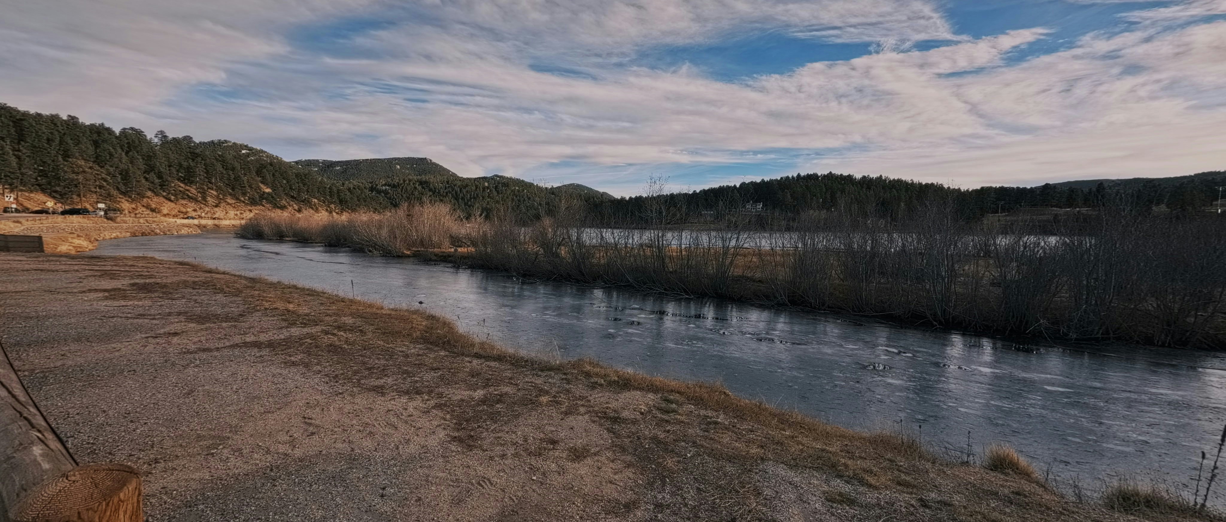 Calm river flows through a landscape with hills and trees.
