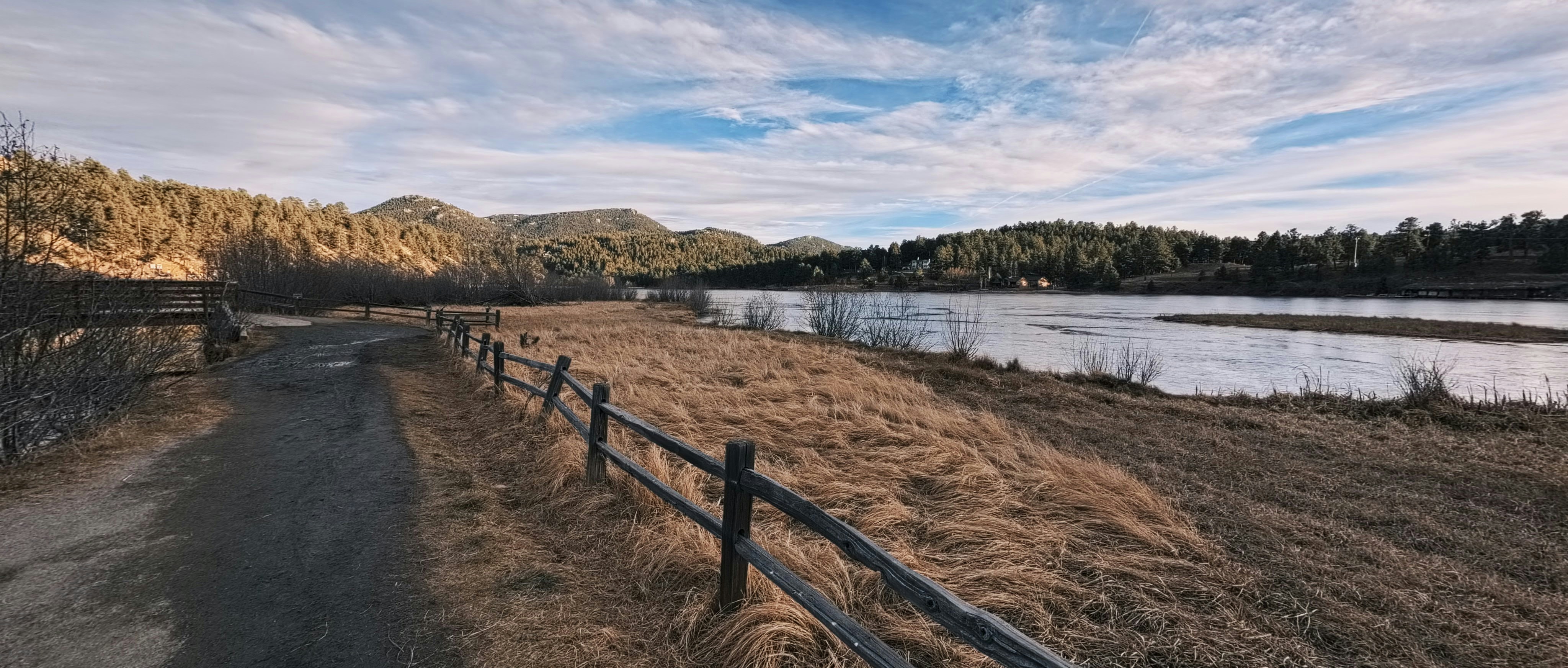 Wooden fence along a path by a calm lake.