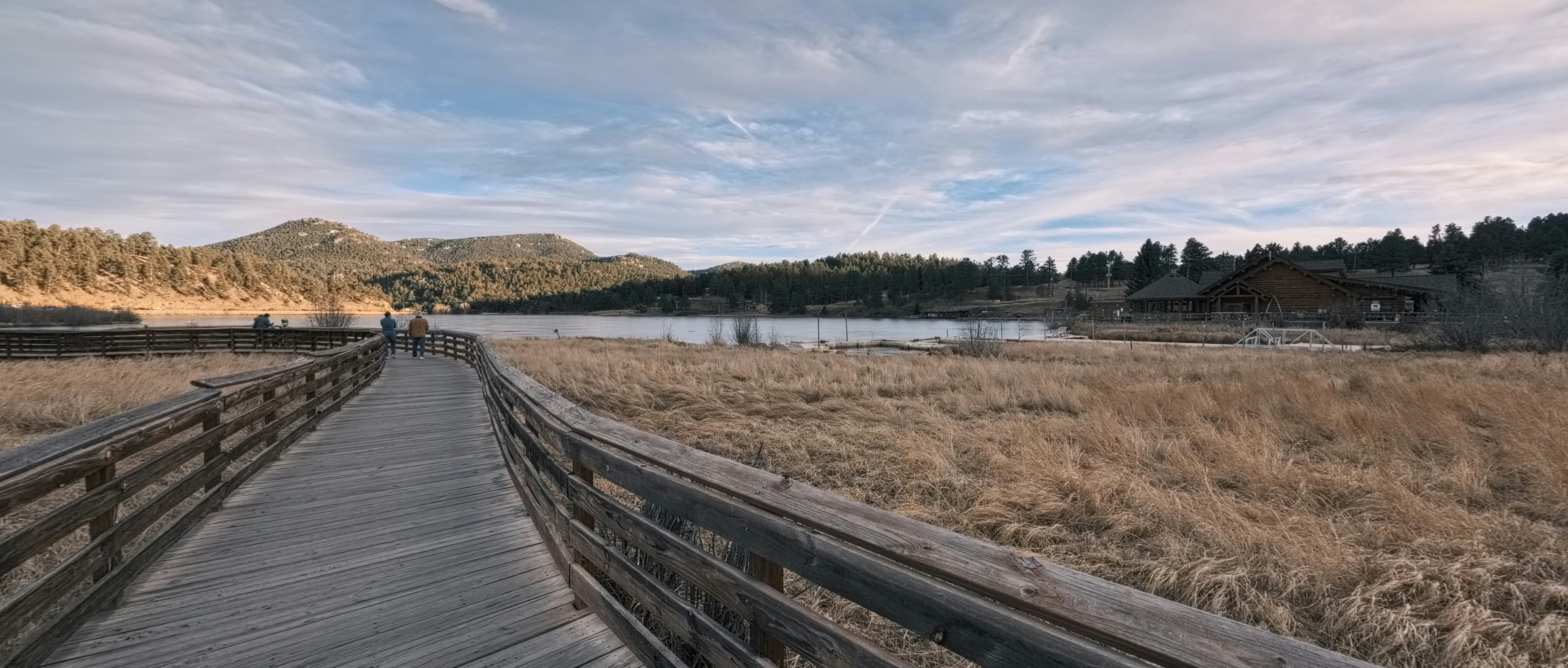 Wooden boardwalk through dry grass to a lake