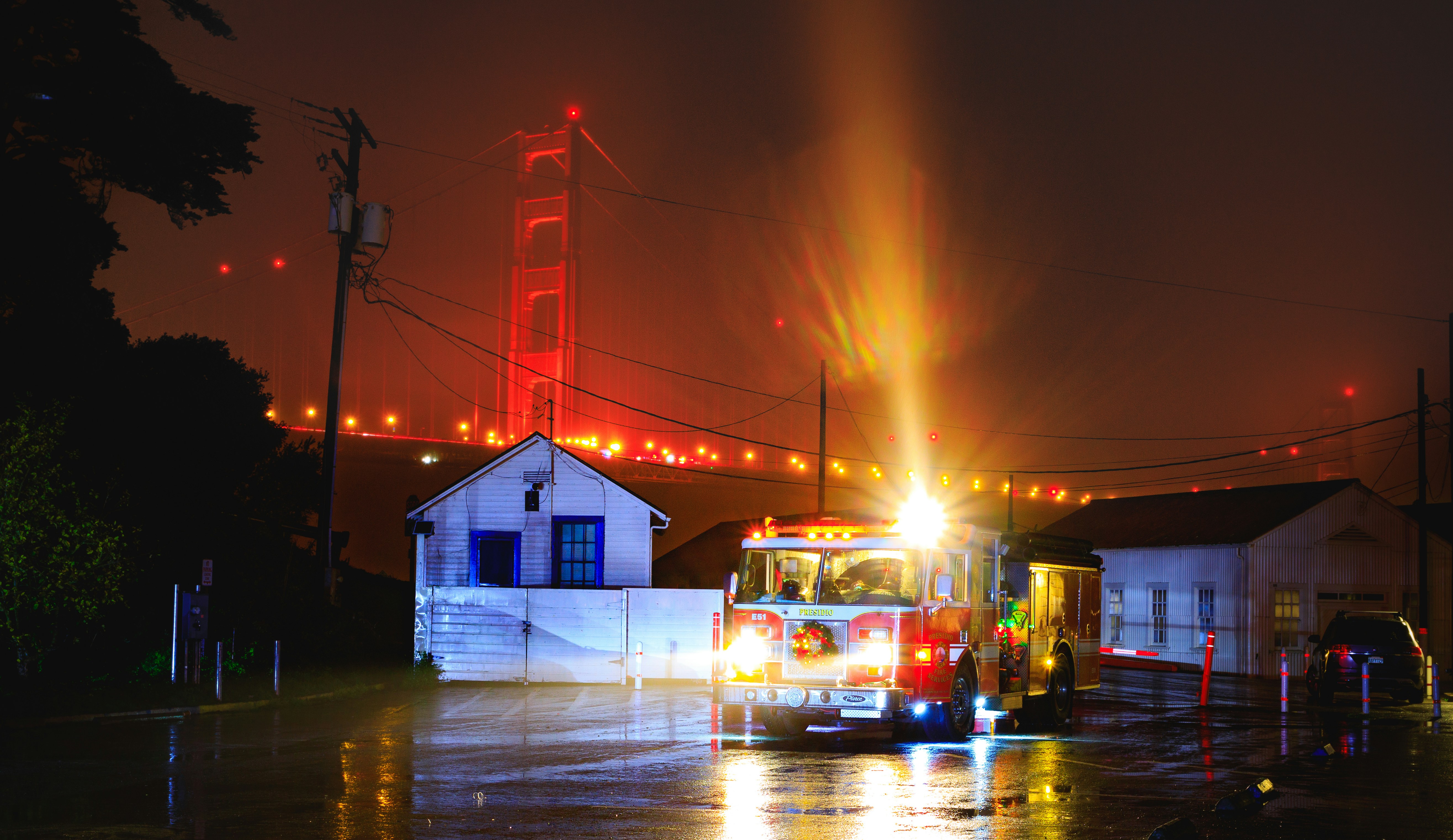 Night Rescue: Fire Truck Illuminates a Rain-Slick Street with Golden Bridge Glow