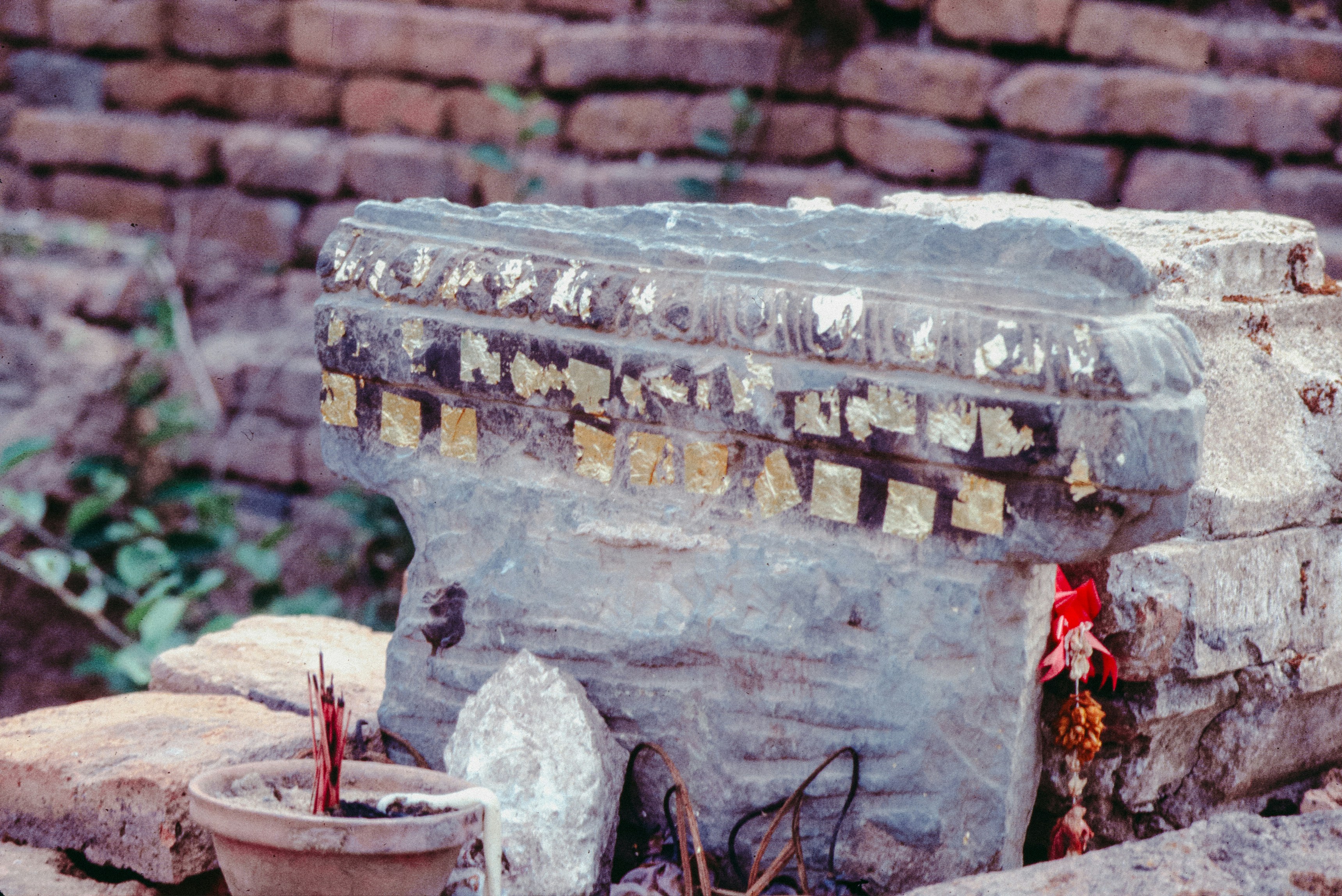 Stone Altar with Worn Carvings and a Red-Flowered Charm