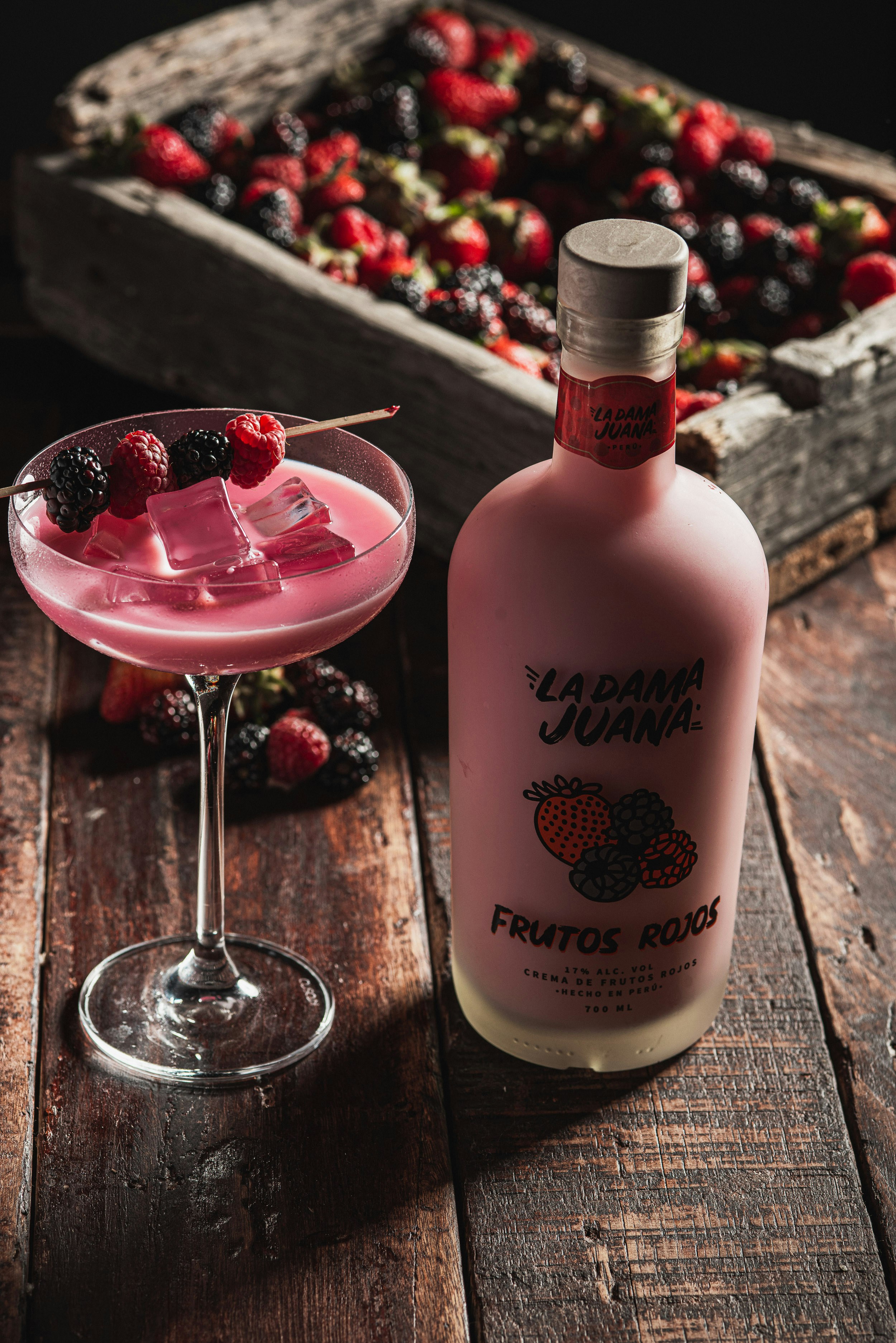 Pink Elixir on a Wooden Stage: Berries, Bottle, and Bokeh-Soft Light