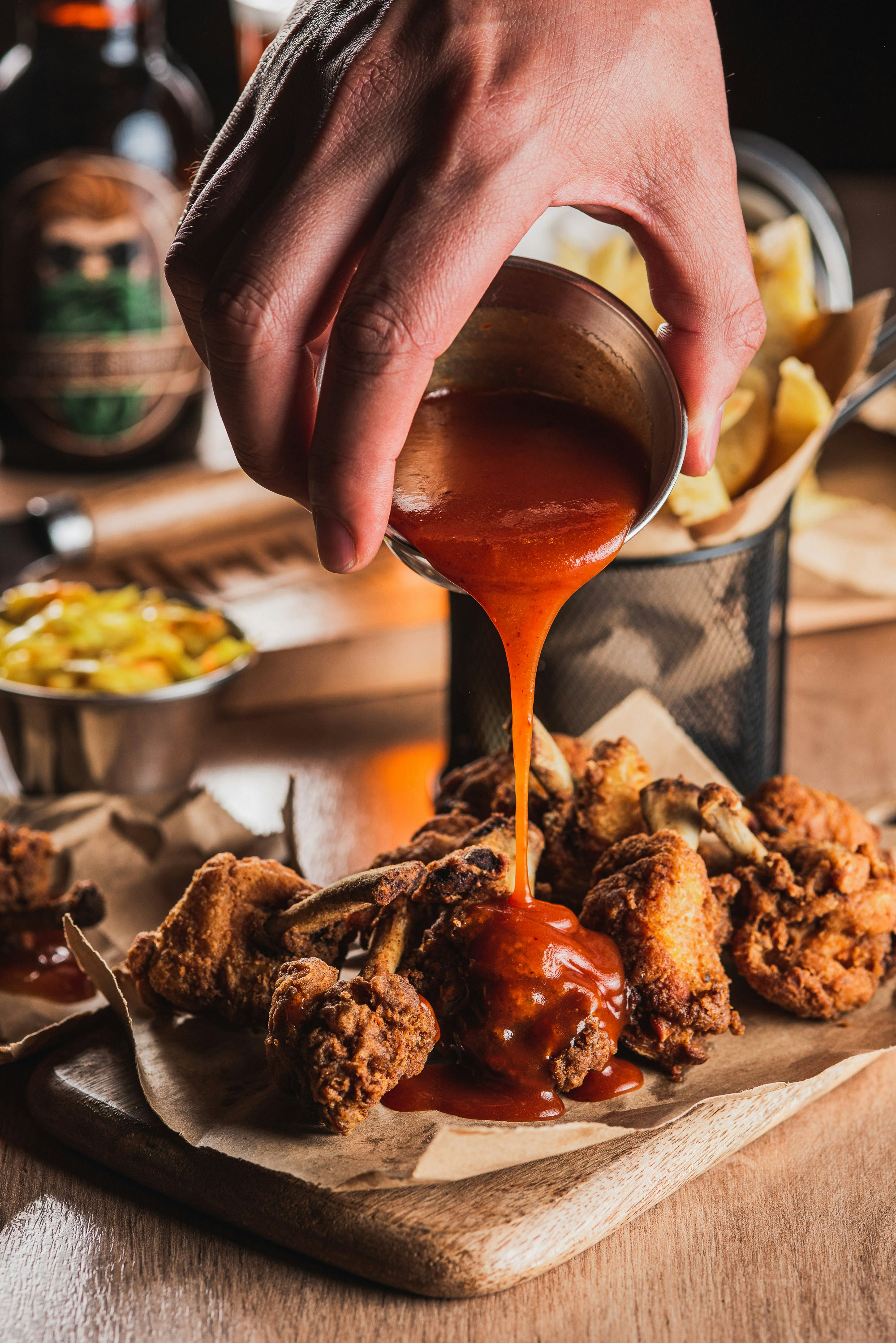 Hand pouring sauce over fried chicken wings. photo – Free Fast food ...