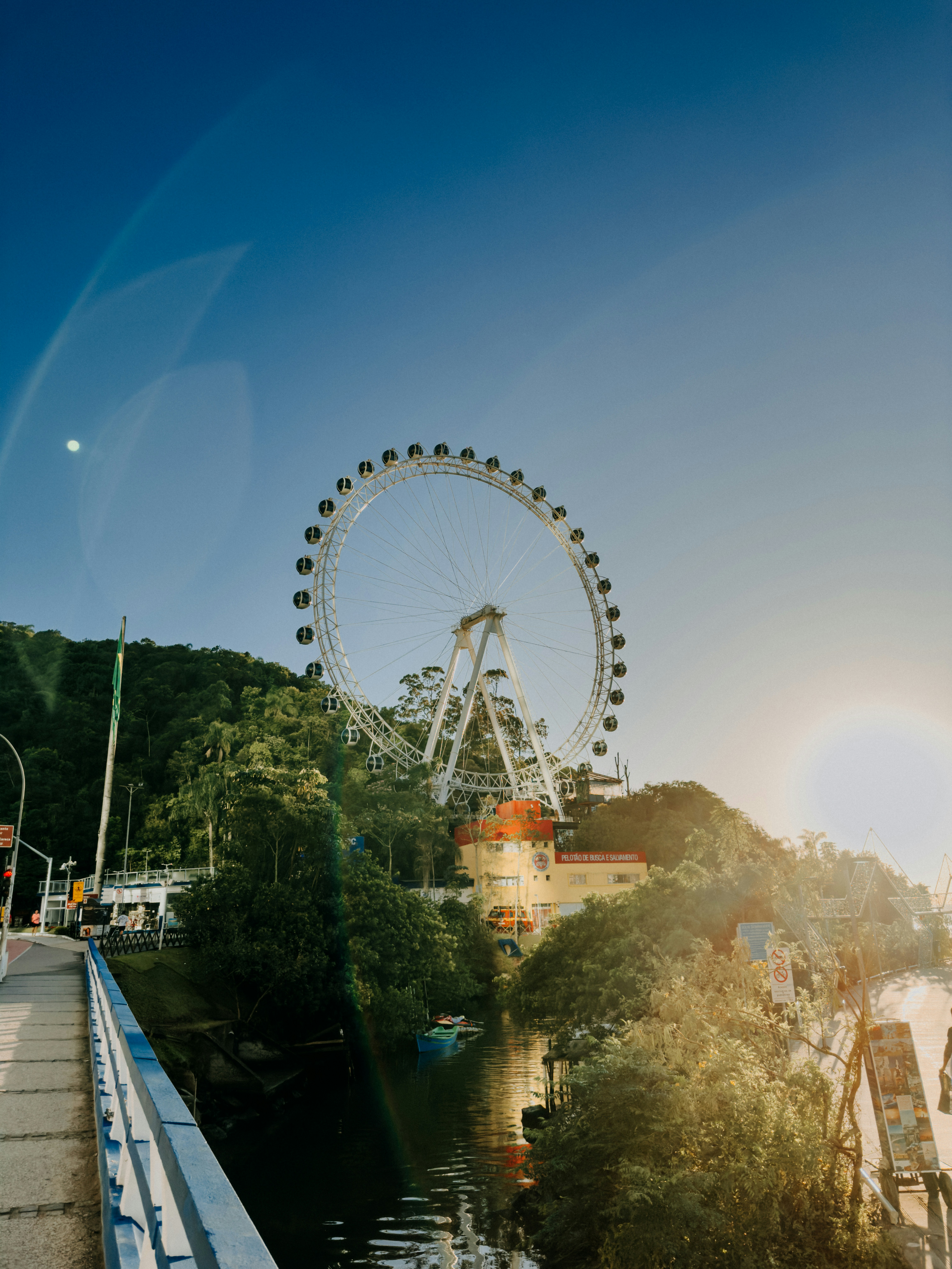 Sunlit Giant Wheel Over River Promenade