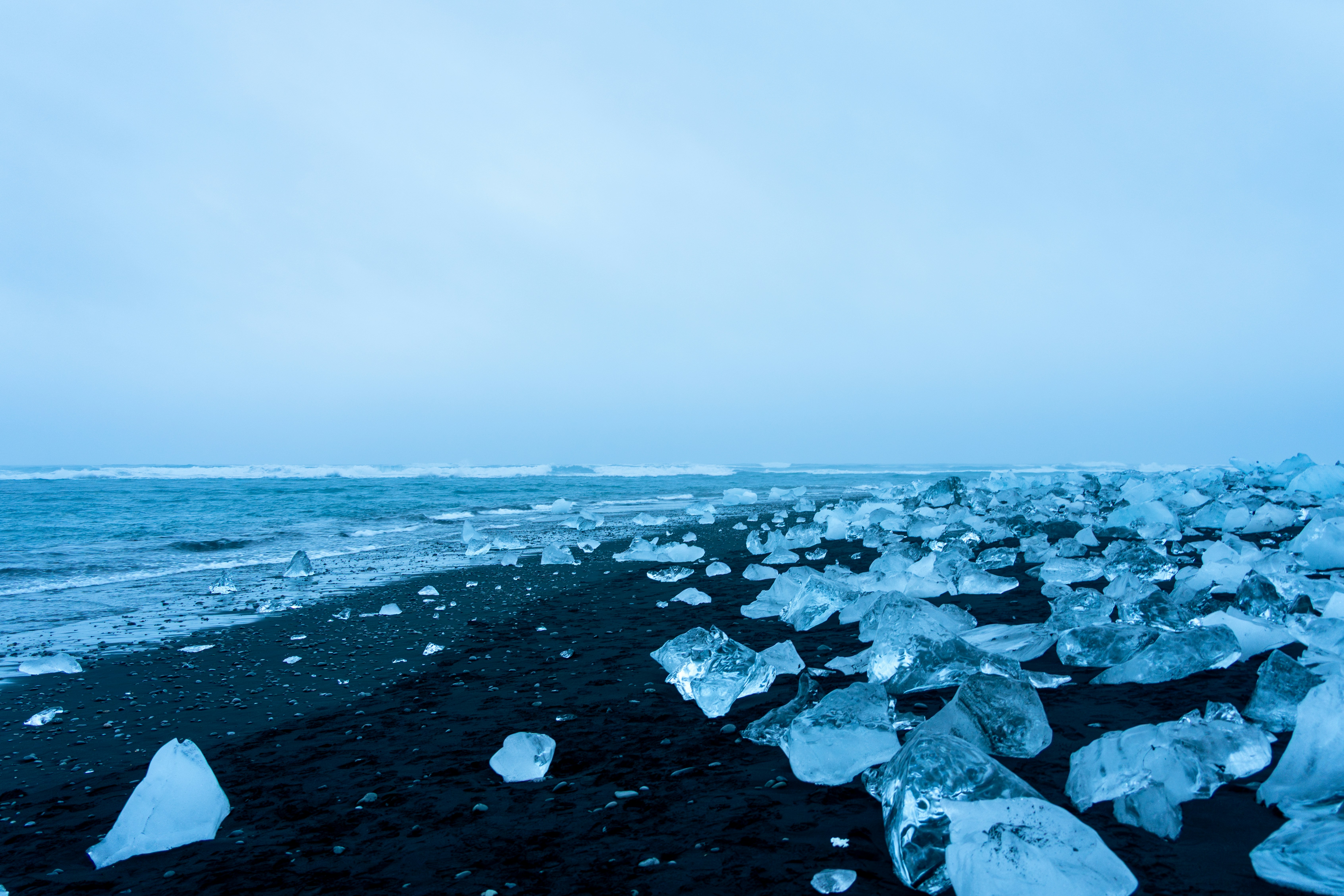 Hielo se desprende en una playa de arena negra junto al mar. foto ...