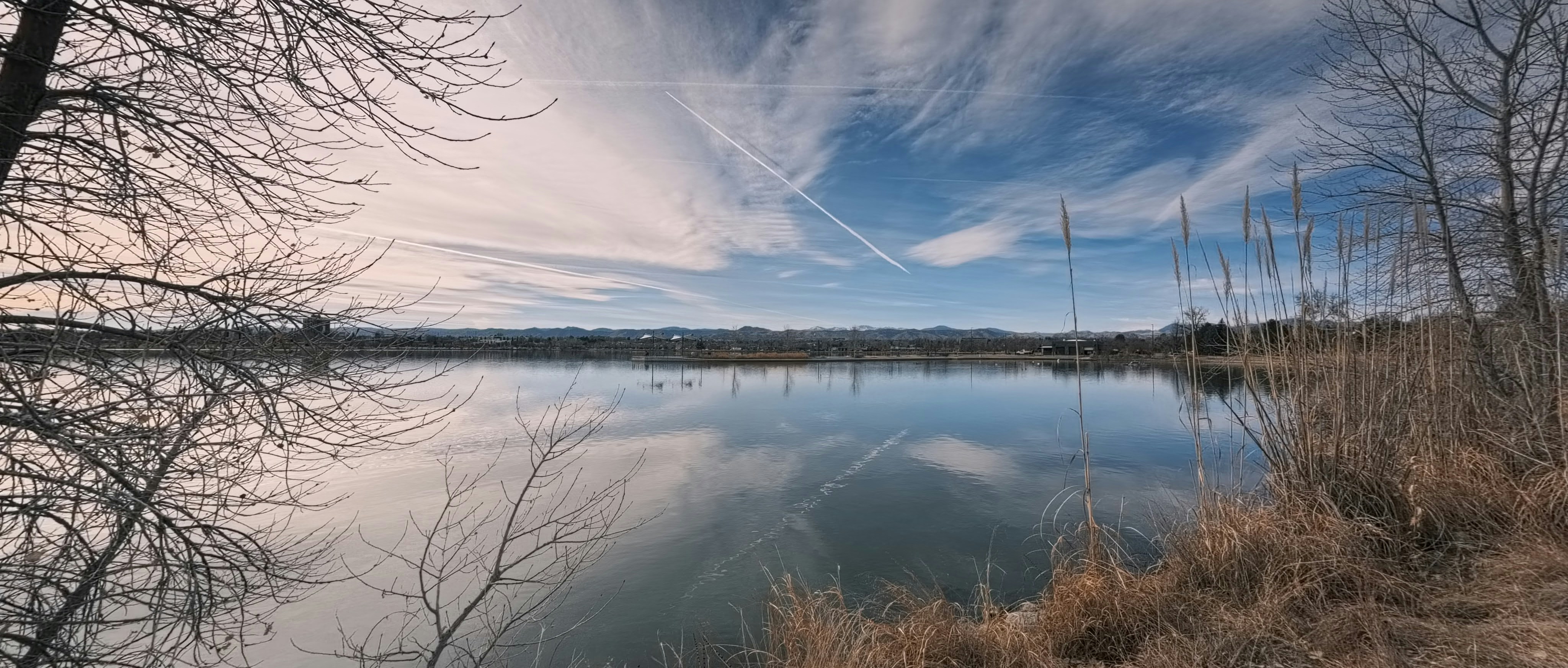 Calm lake reflecting a cloudy blue sky at sunset