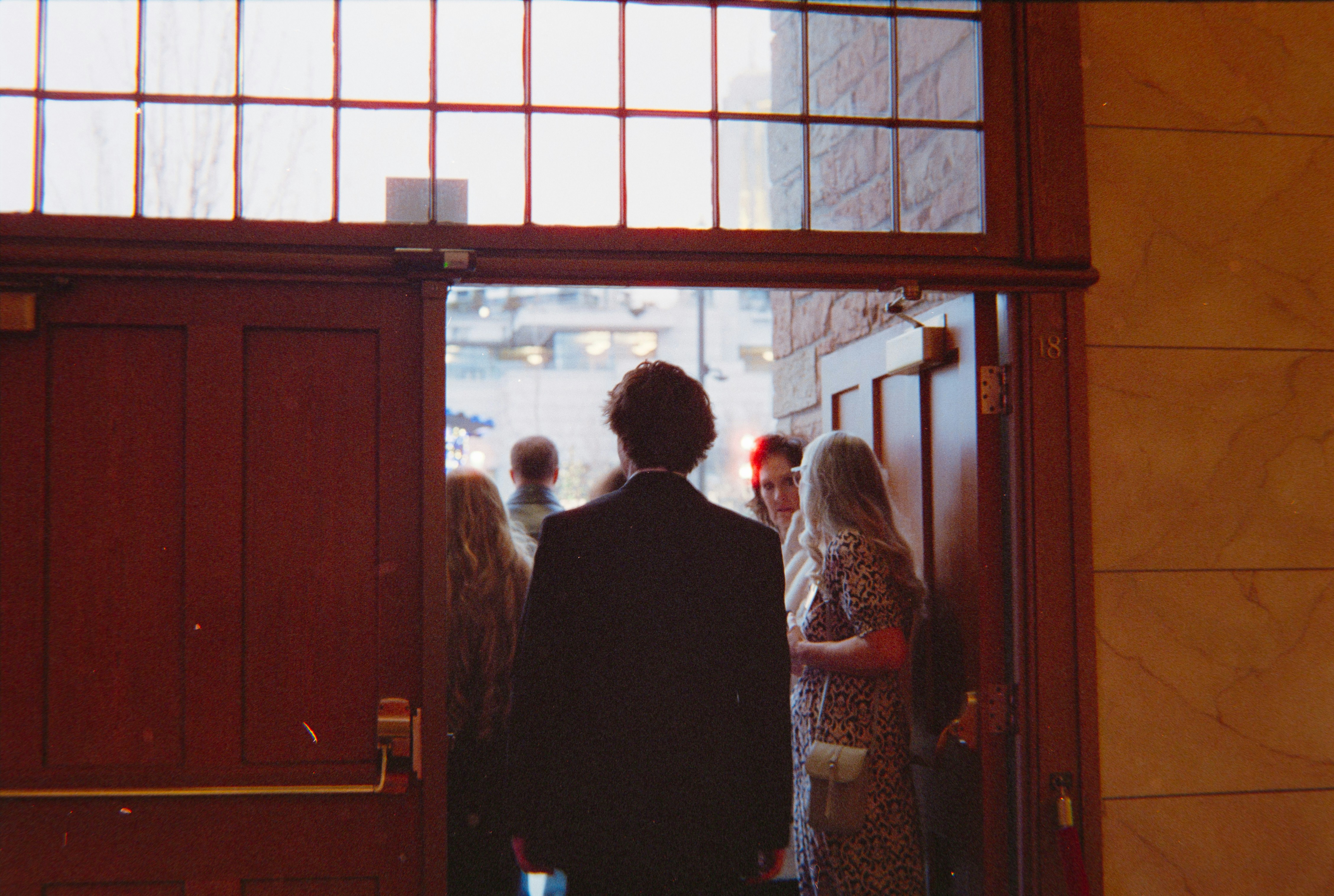 Through the Entrance: silhouettes and conversation in a dim lobby