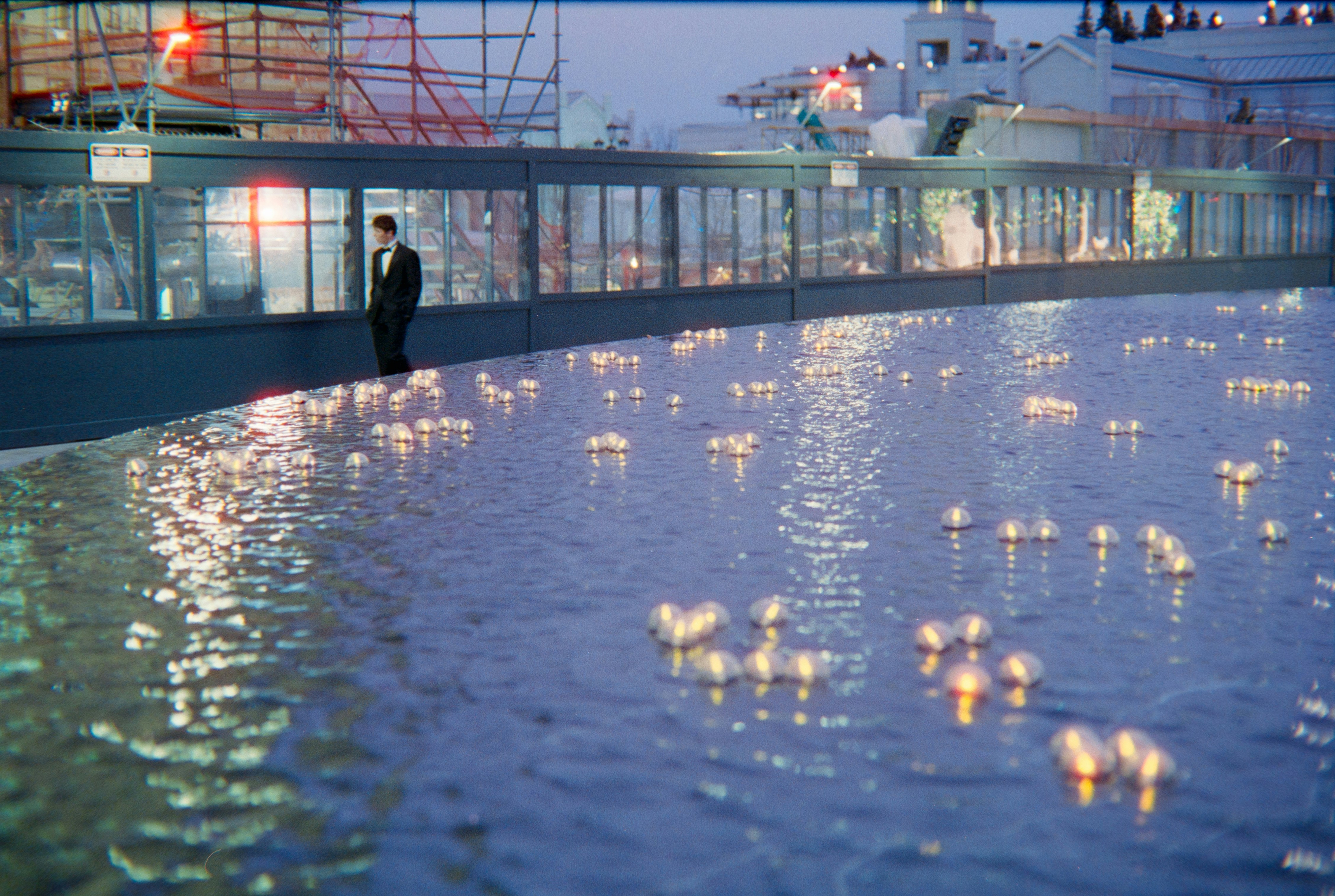 Lonely Figure on a Lit Walkway over a Reflective Waterfront
