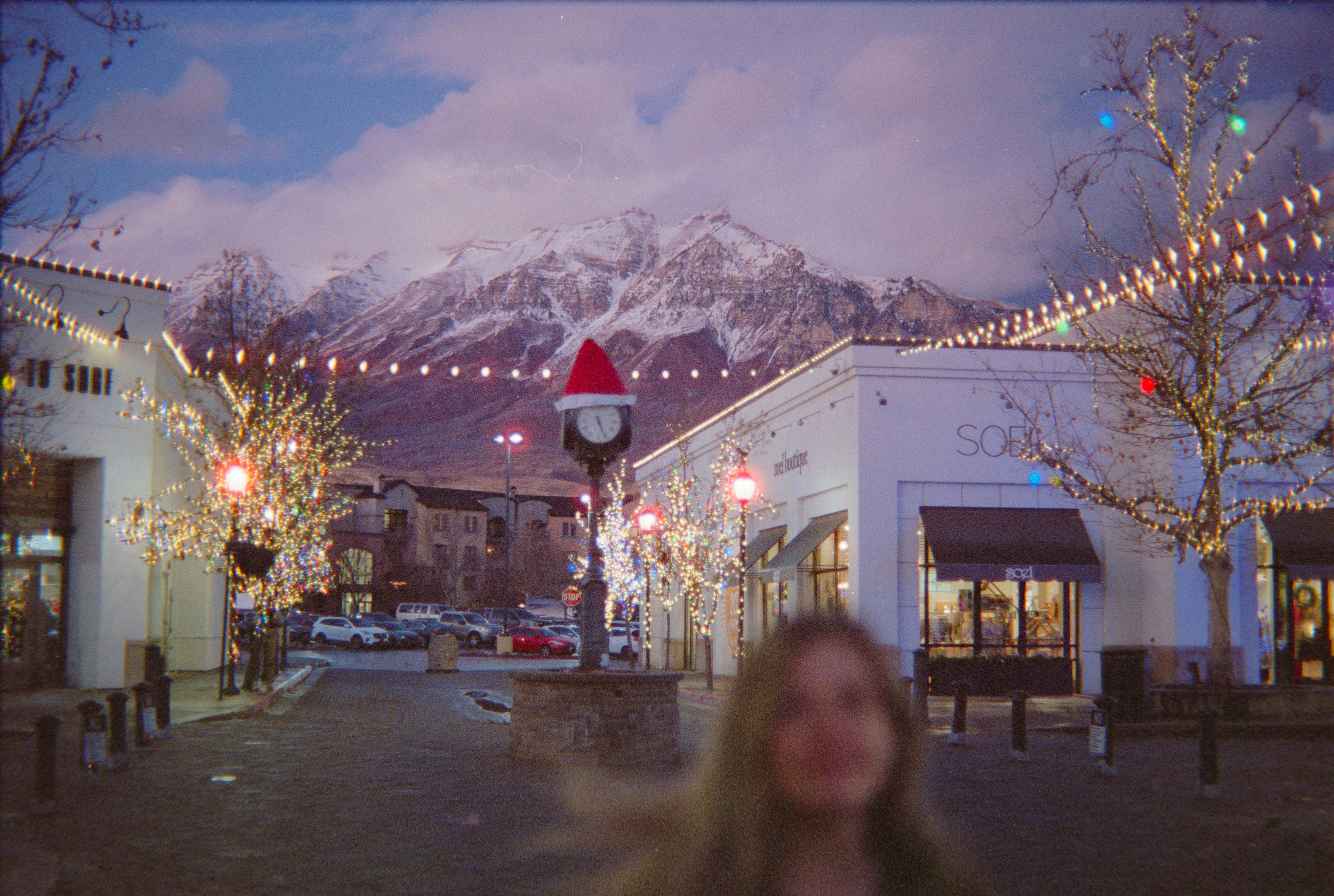Holiday Lights Over a Quiet Town Square with a Blurred Foreground Figure