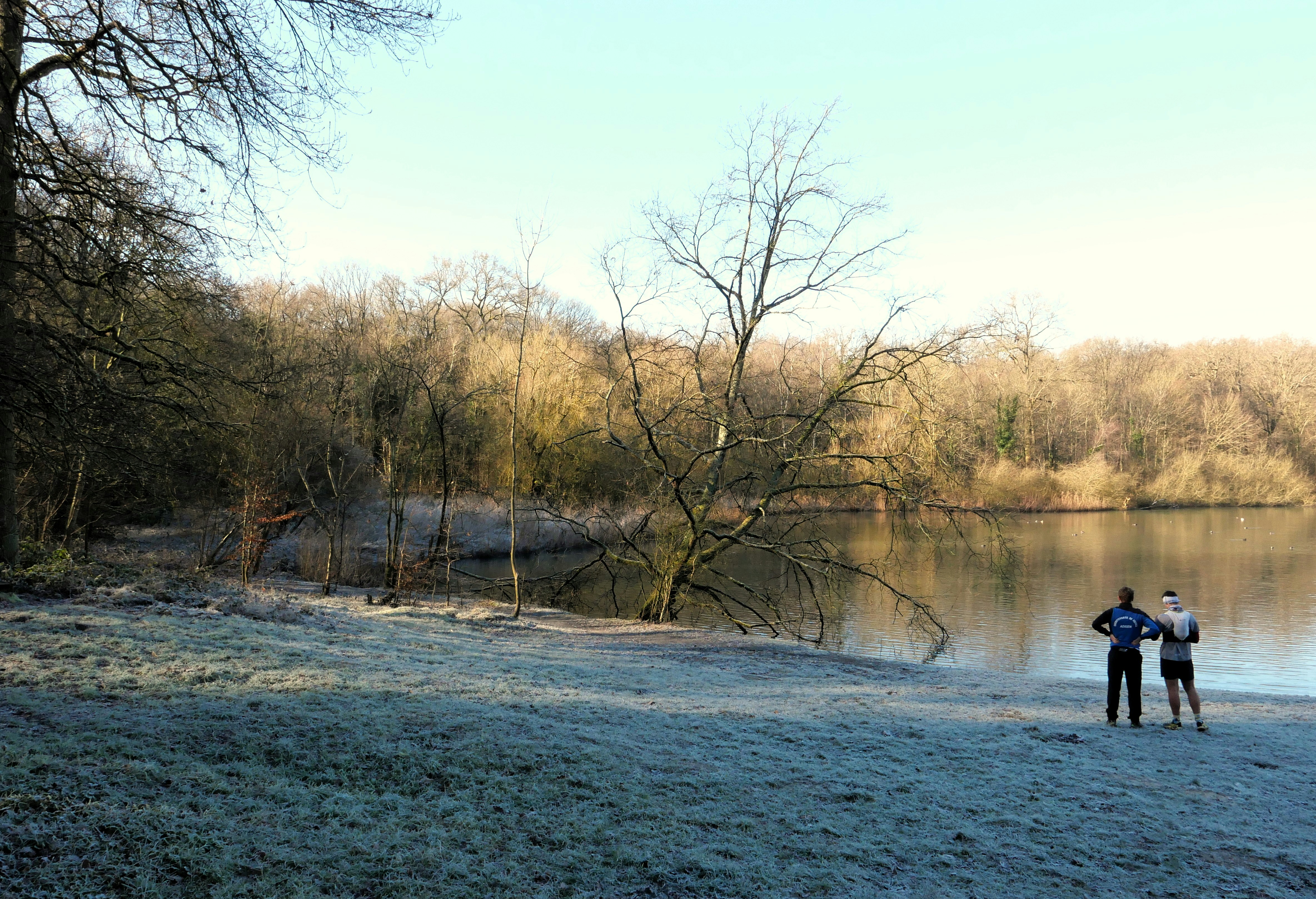 Two hikers by the frost-kissed lakeshore at daybreak
