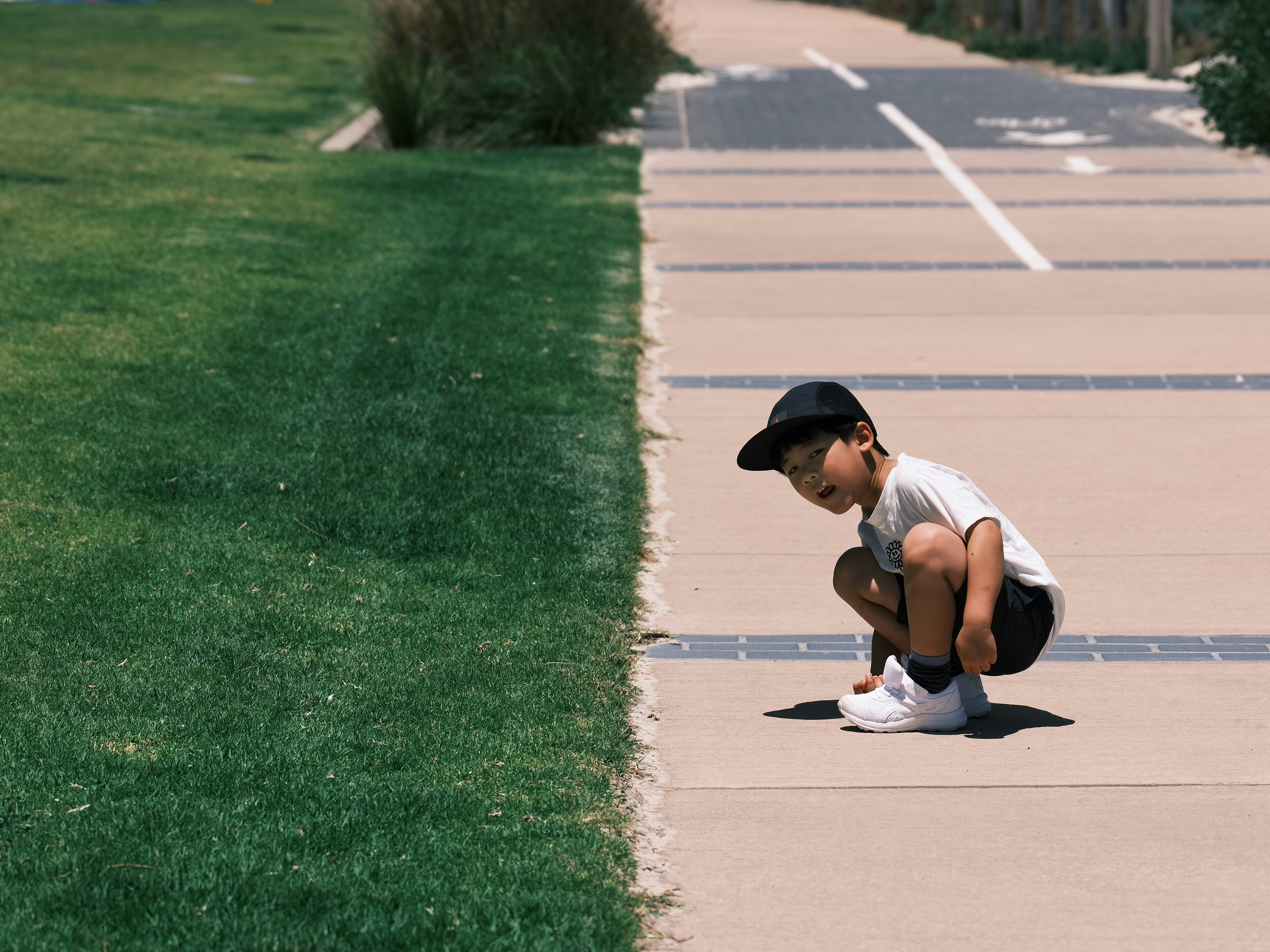 A young boy crouches on a paved path. photo – Free Summer Image on Unsplash