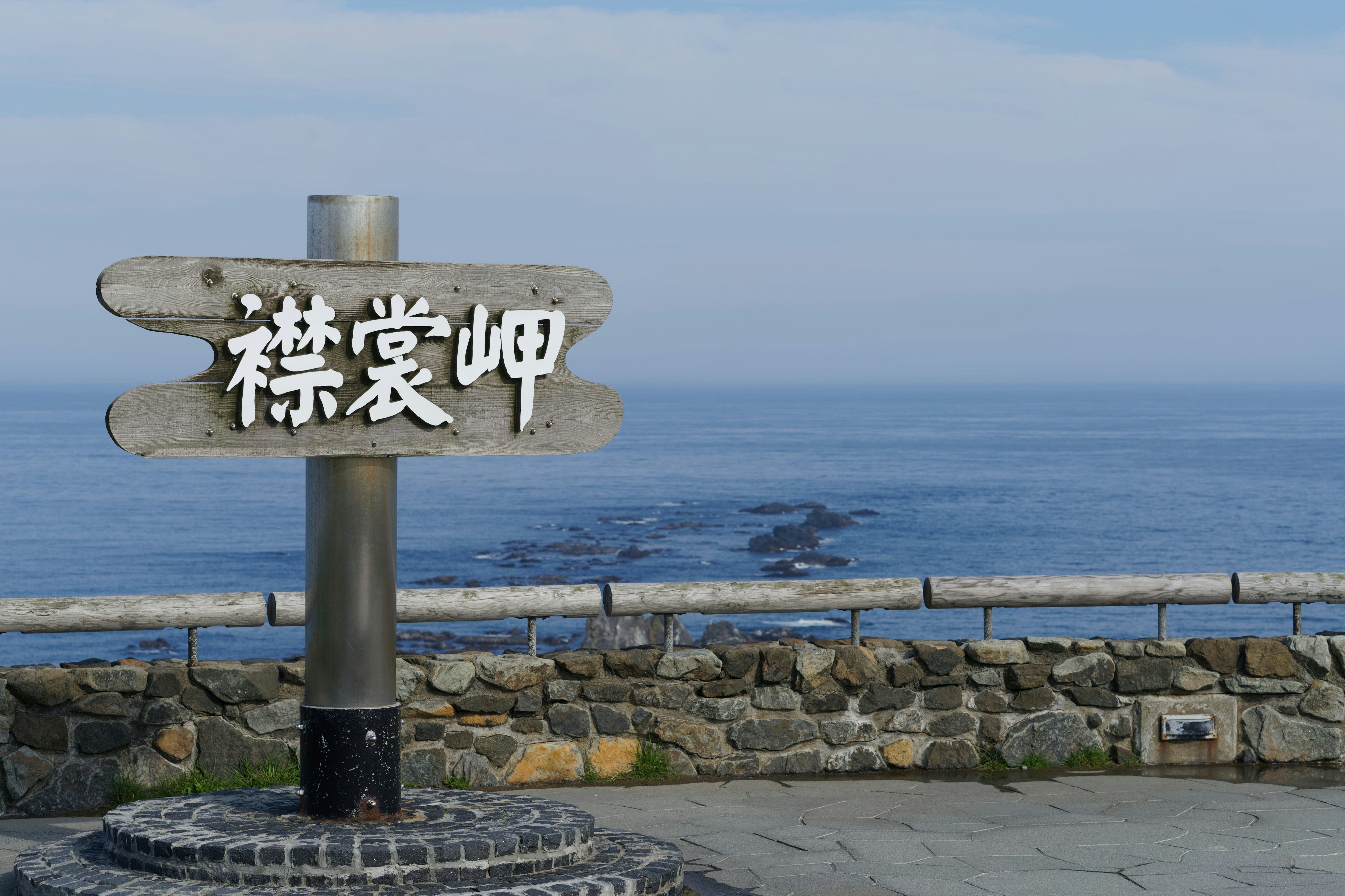 Wooden signpost with japanese text by the ocean