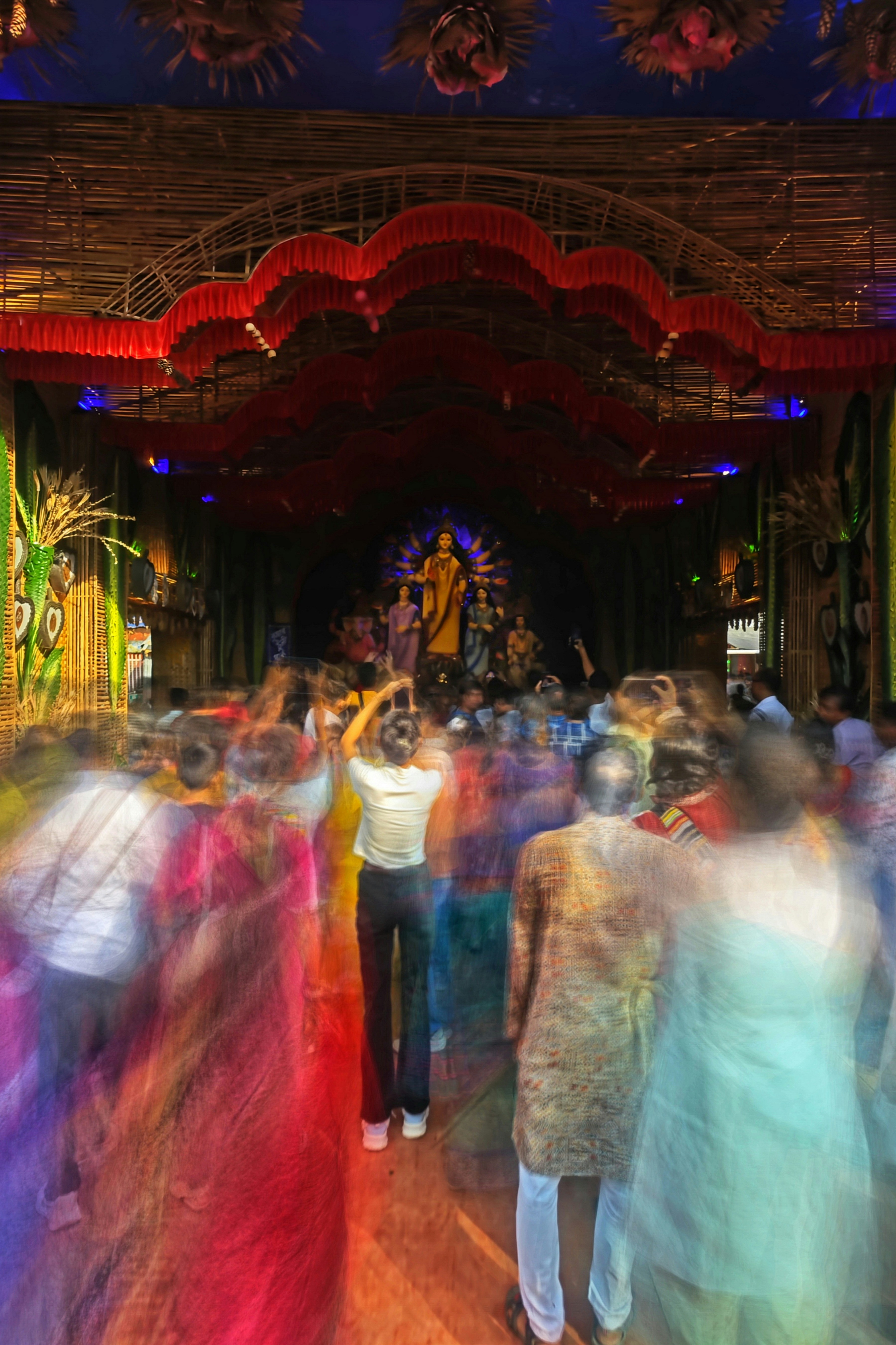 Crowd gathered at a festival with deity in background