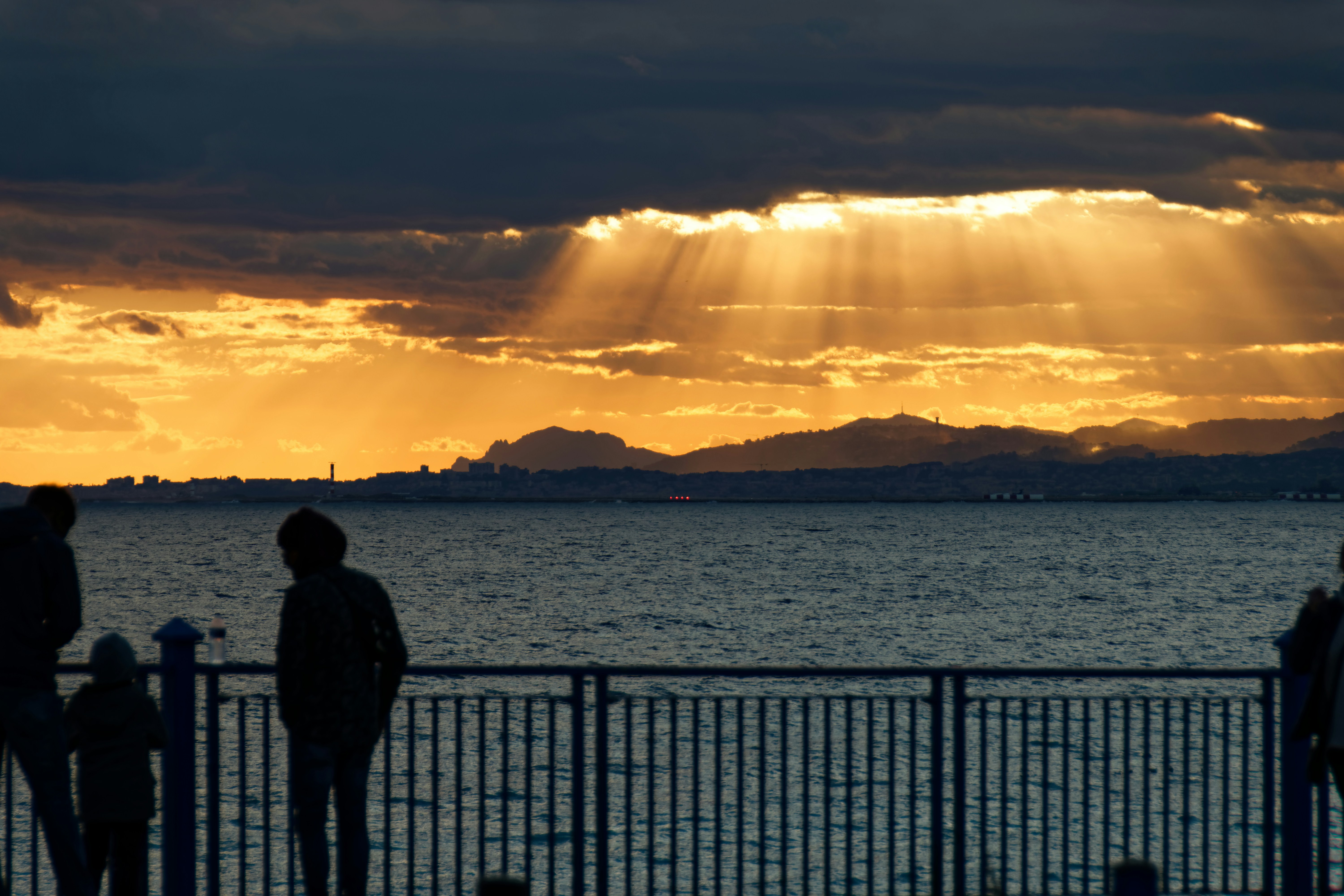 Sunlit Break: Silhouetted Figures by the Seawall at Dusk