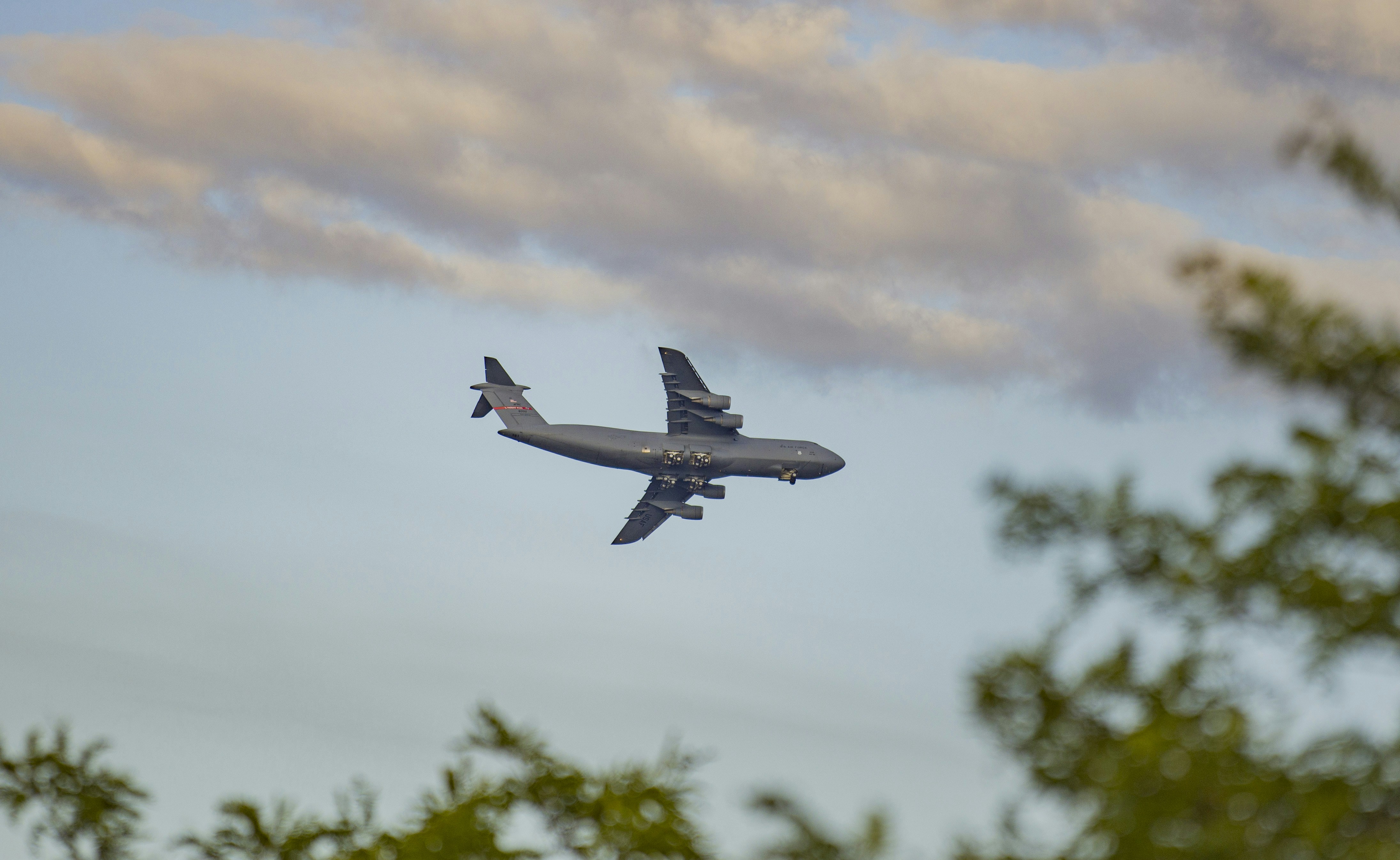 Equipped for Flight: a C-130-like aircraft glides above a treetop frame