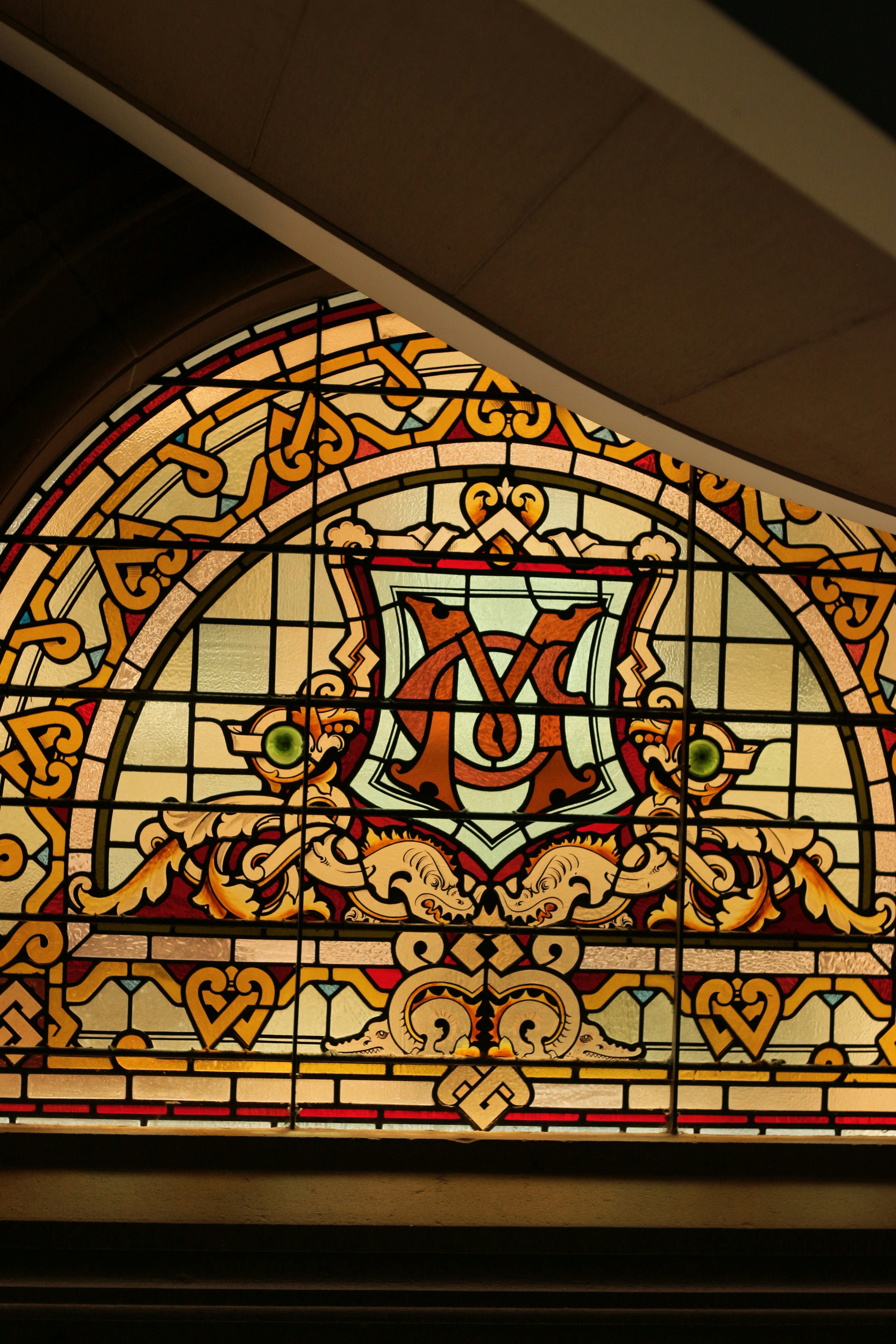 Heraldic Glass: Central emblem Amid Intricate Ornamental Arch