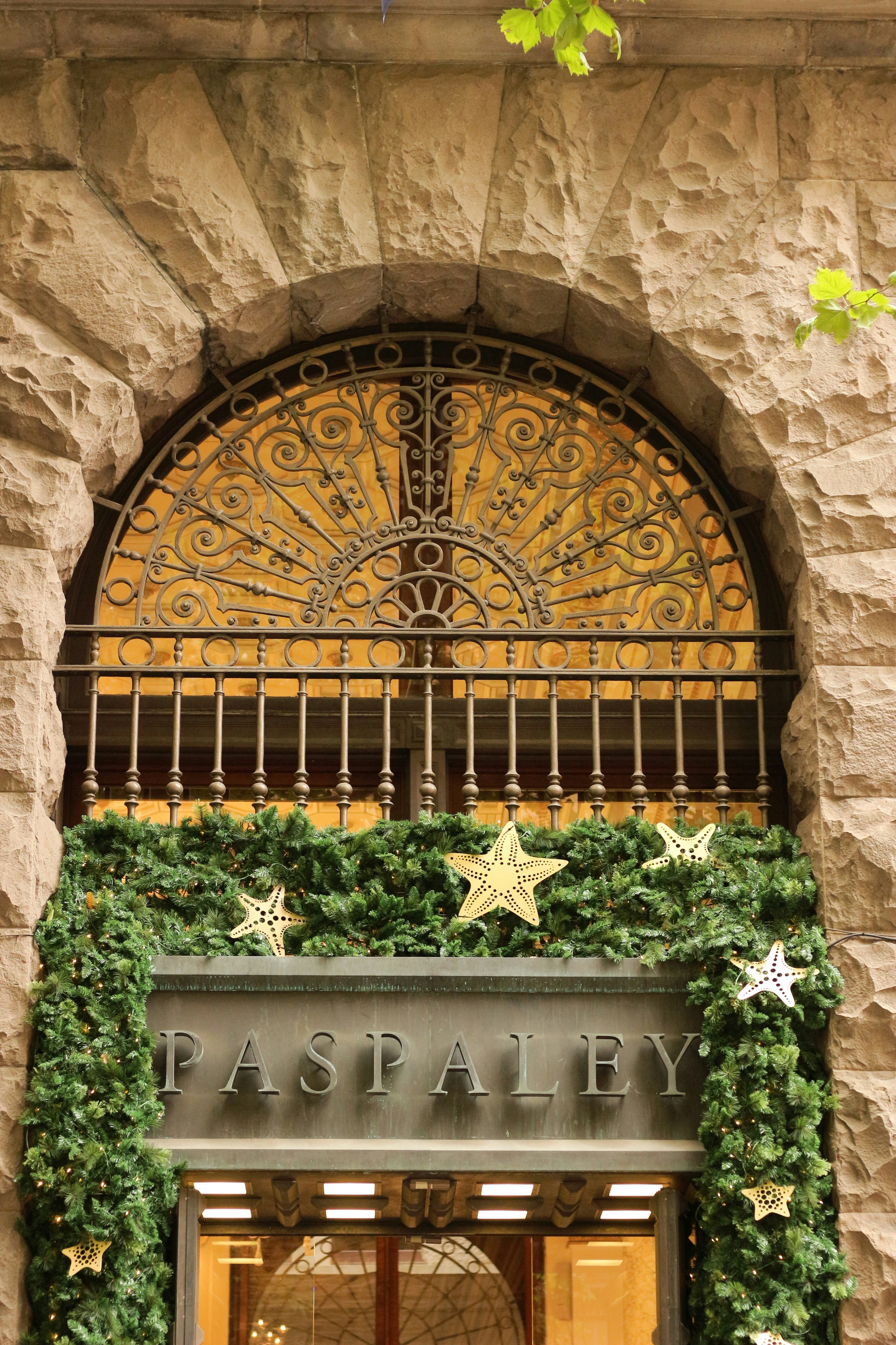 Arched doorway in stone facade framed by festive greenery and star ornaments