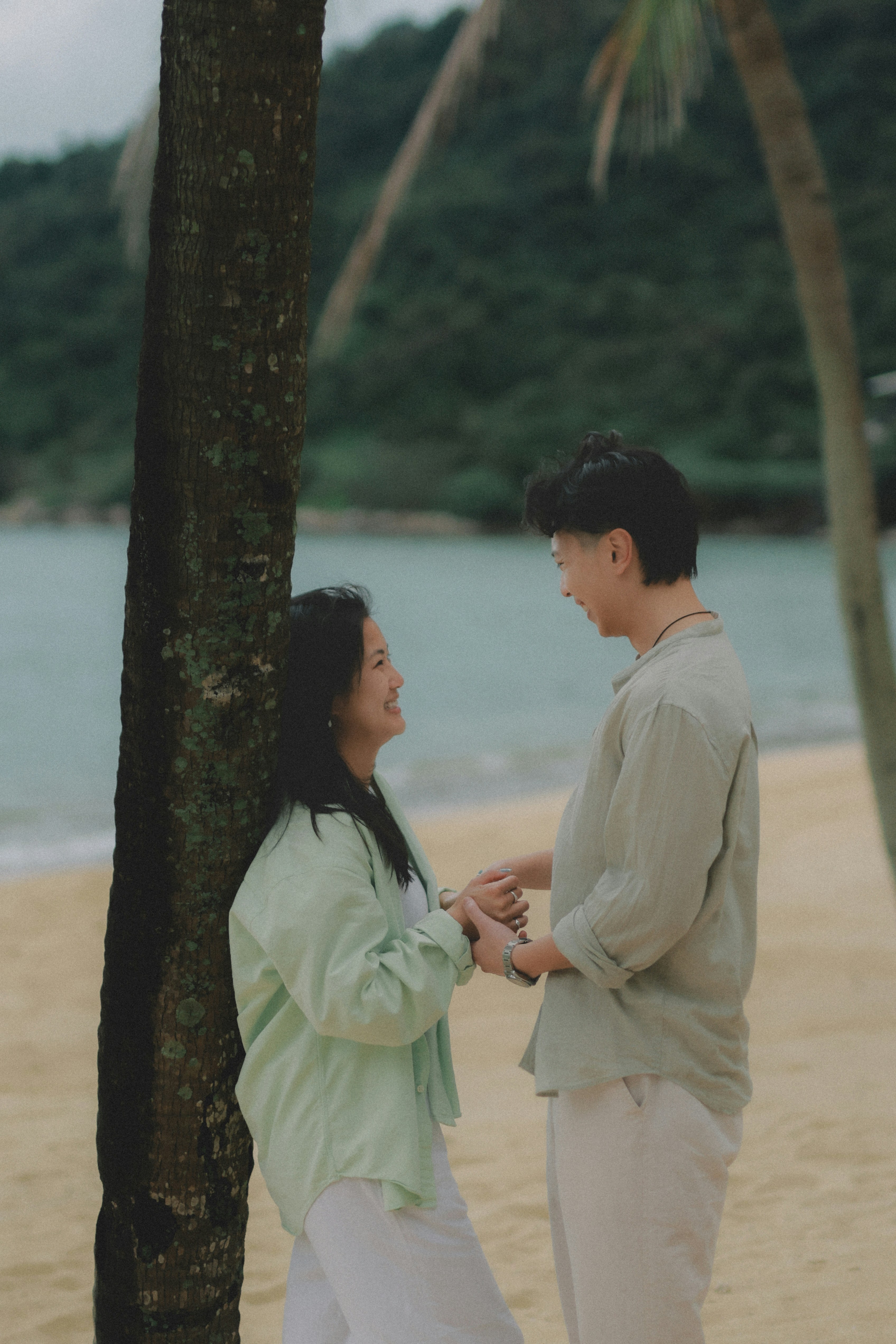 Holding hands under a palm-fringed shoreline