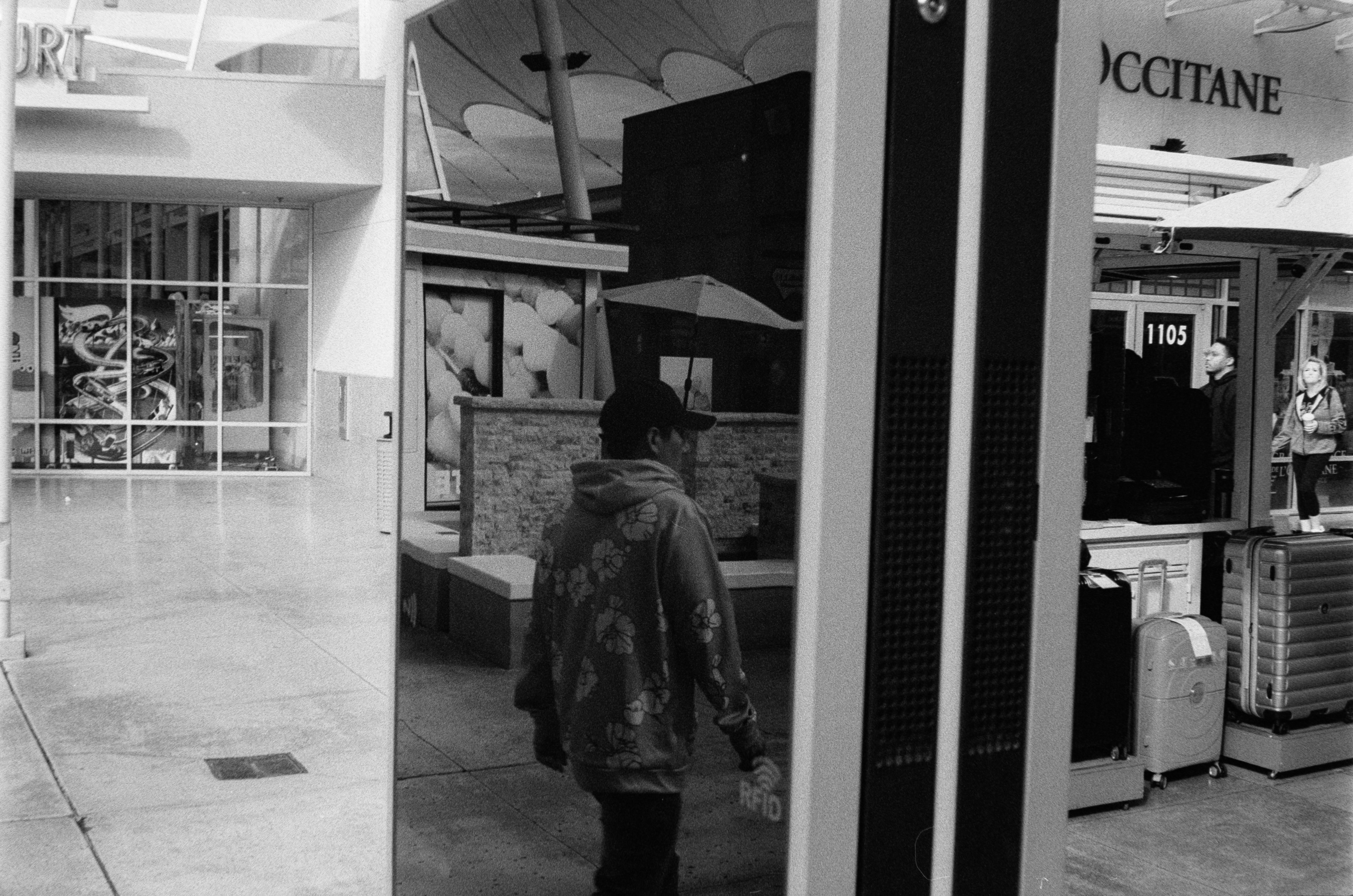 Traveler in a Modern Courtyard: Mono Moments in a Mall Arcade