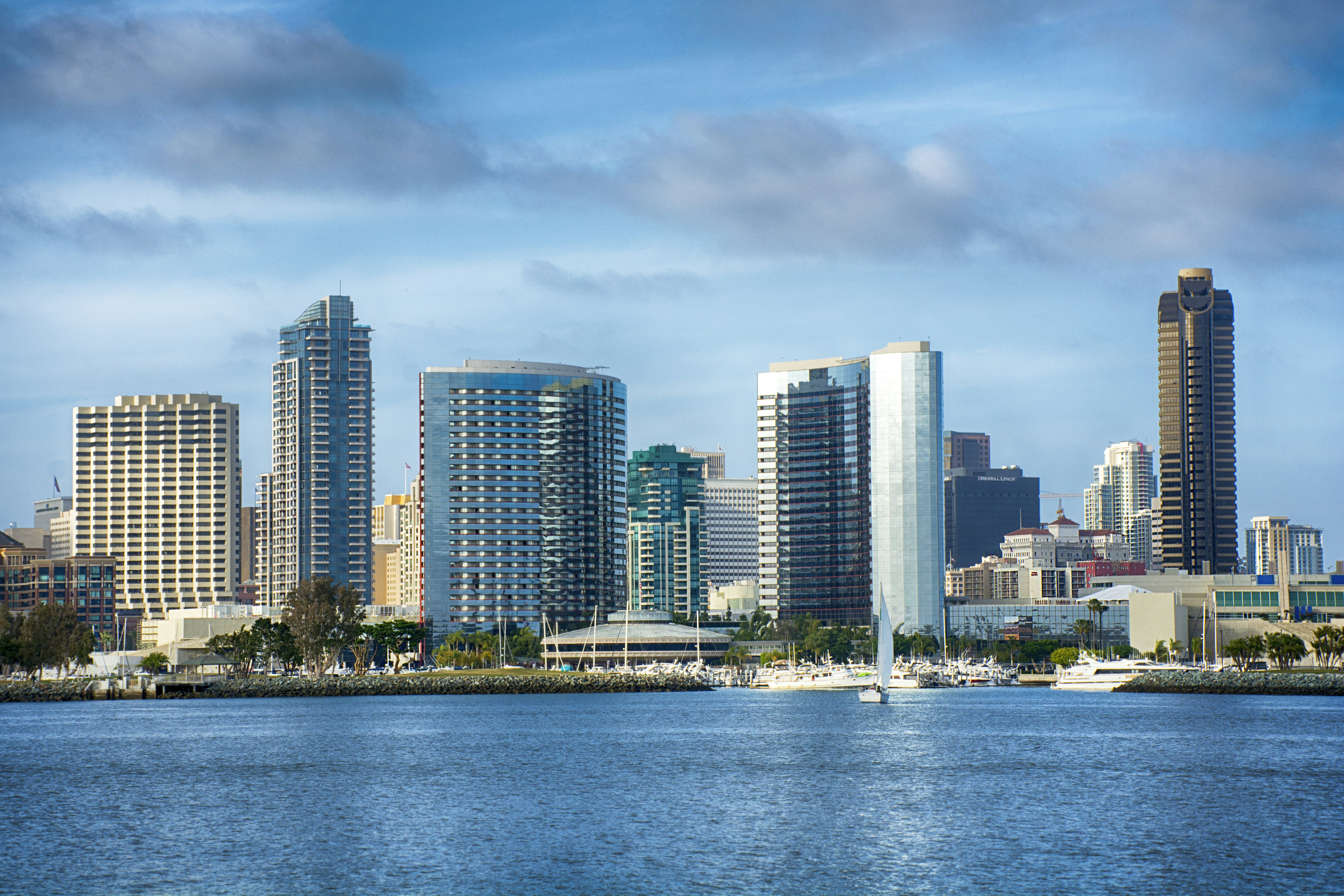 Description: A breathtaking wide-angle view of the San Diego city skyline as seen from across the bay. The architectural diversity of the downtown skyscrapers—including the iconic twin towers of the Manchester Grand Hyatt—is captured during the "blue hour," with city lights beginning to twinkle and reflect off the calm Pacific waters. In the foreground, the gentle wake of the bay adds a sense of movement to this quintessential Southern California scene. Ideal for travel editorials, urban lifestyle content, and Califor