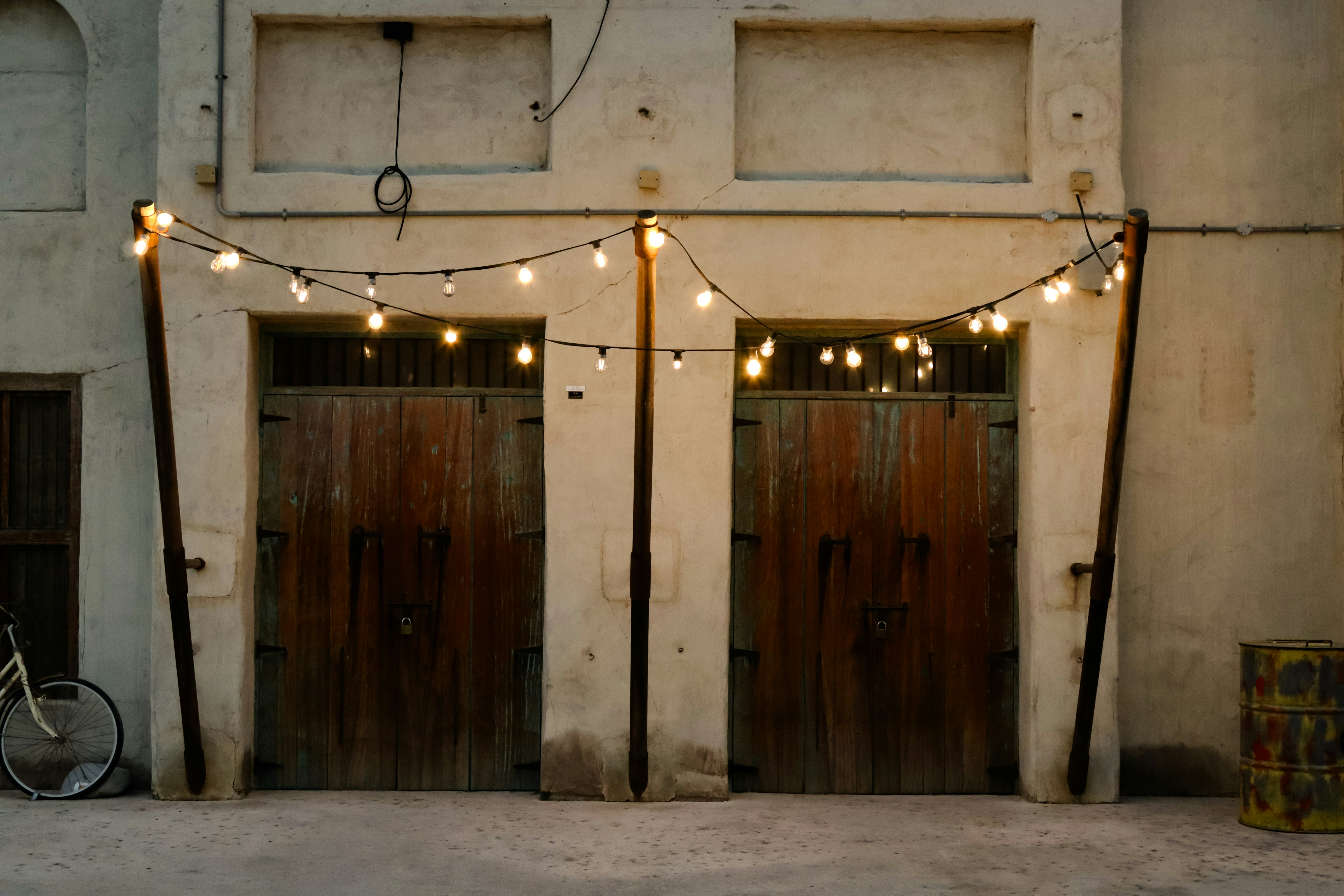 String Lights over Weathered Doors in Quiet Courtyard