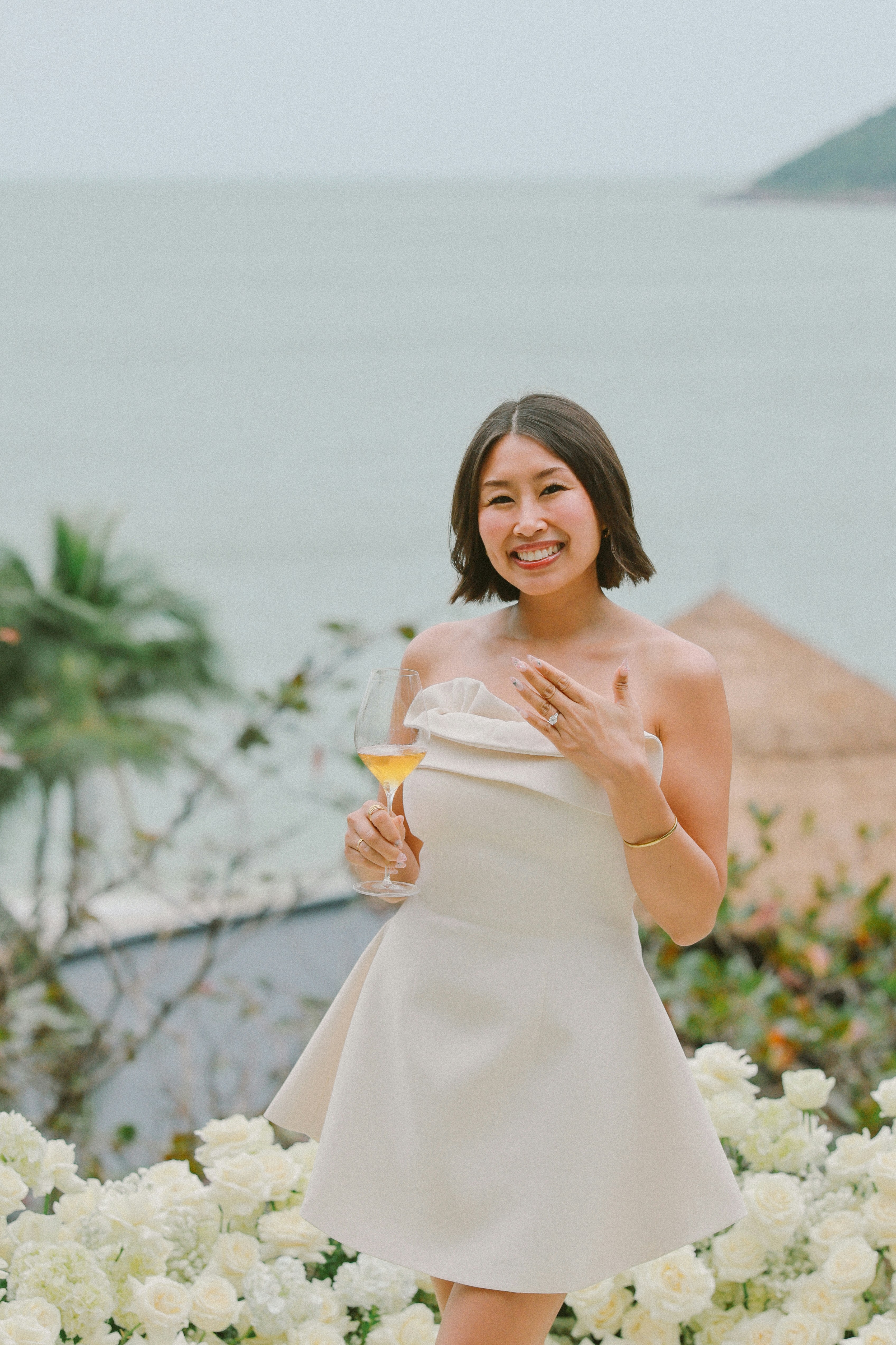 Bridal toast by the shoreline: a radiant smile amid white blooms