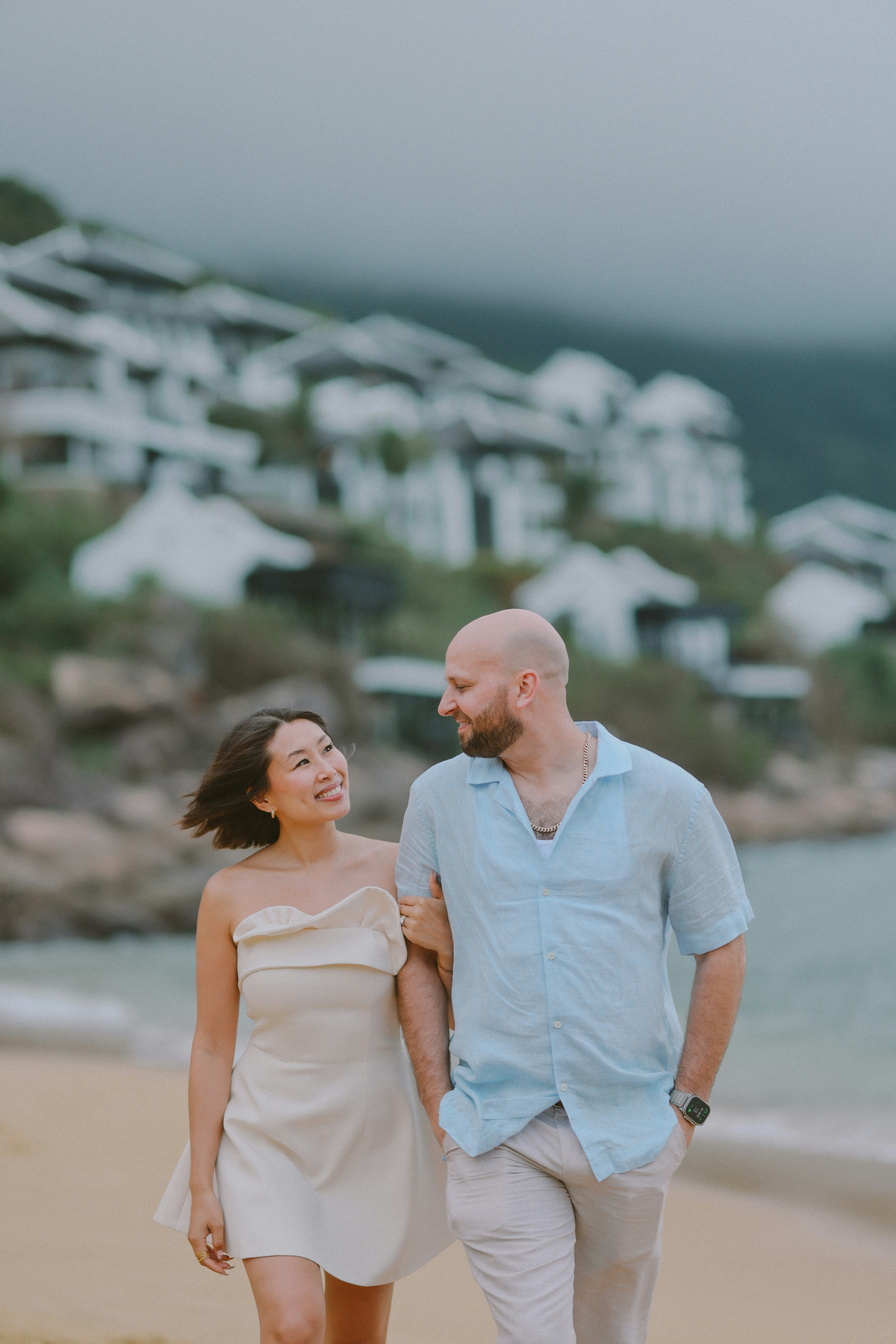 Couple walking on a beach near white buildings. photo – Free Beach ...