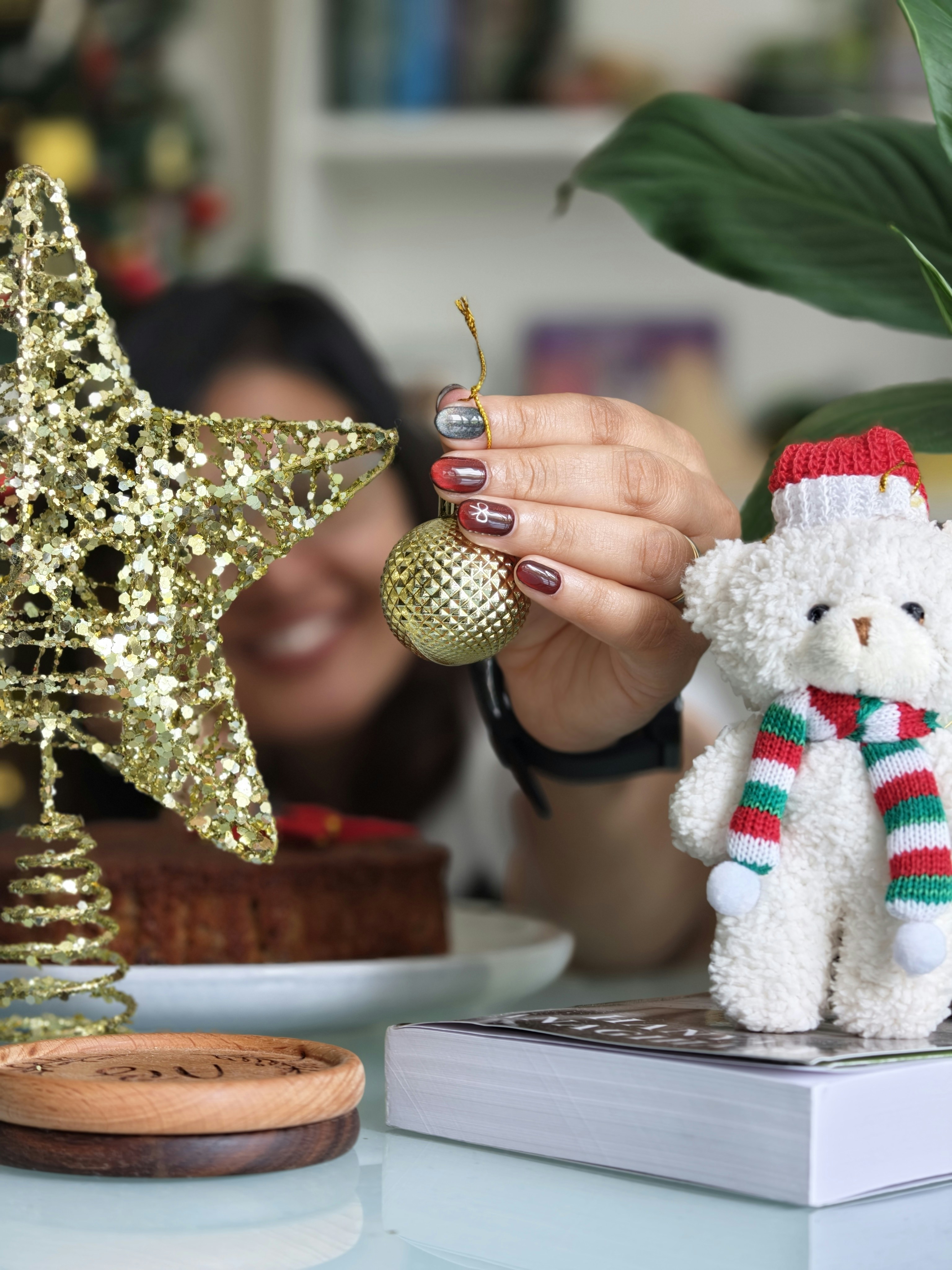 Woman decorating christmas tree with ornaments and teddy bear