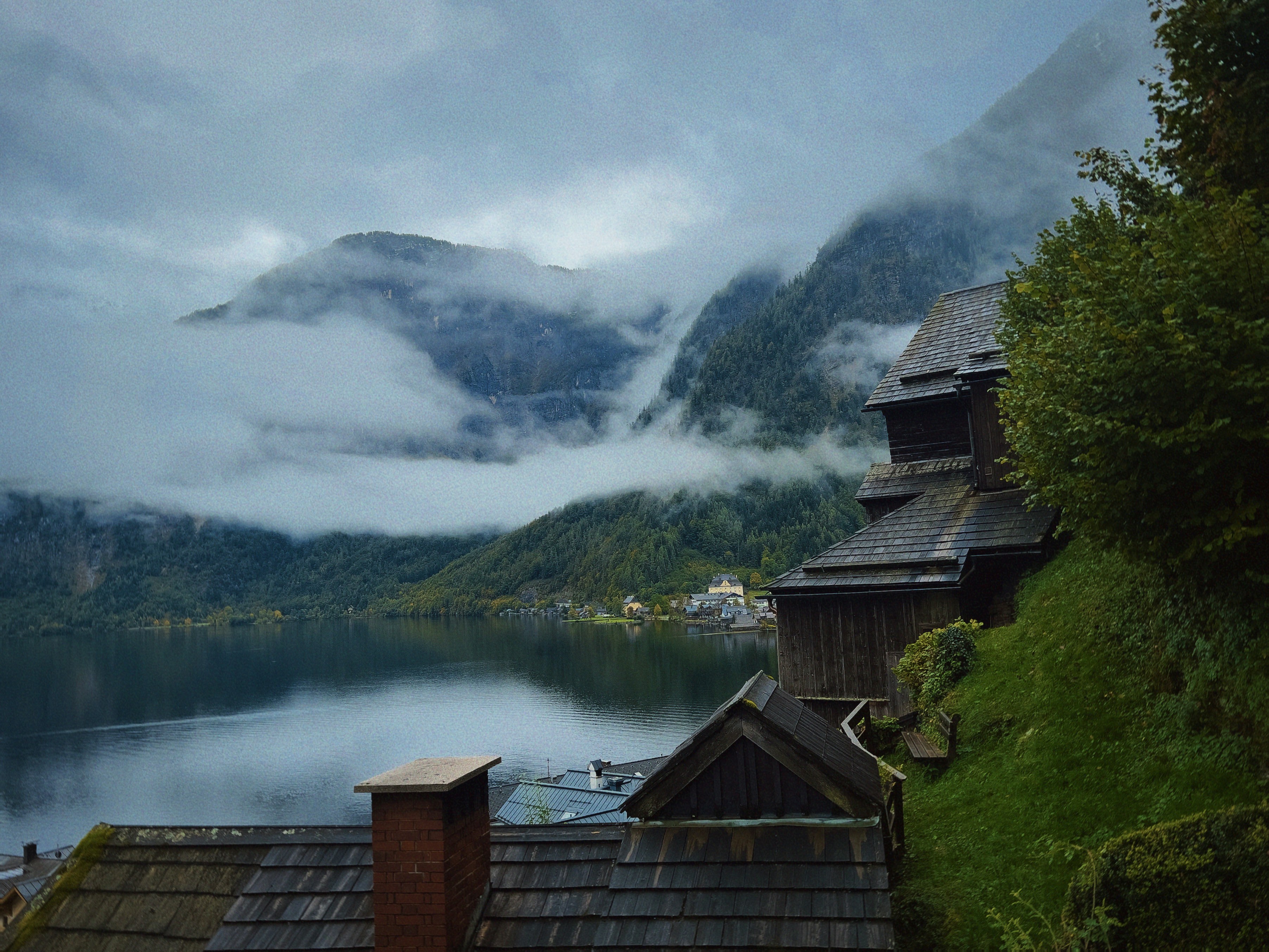 Misty mountains over a calm lake with village houses.