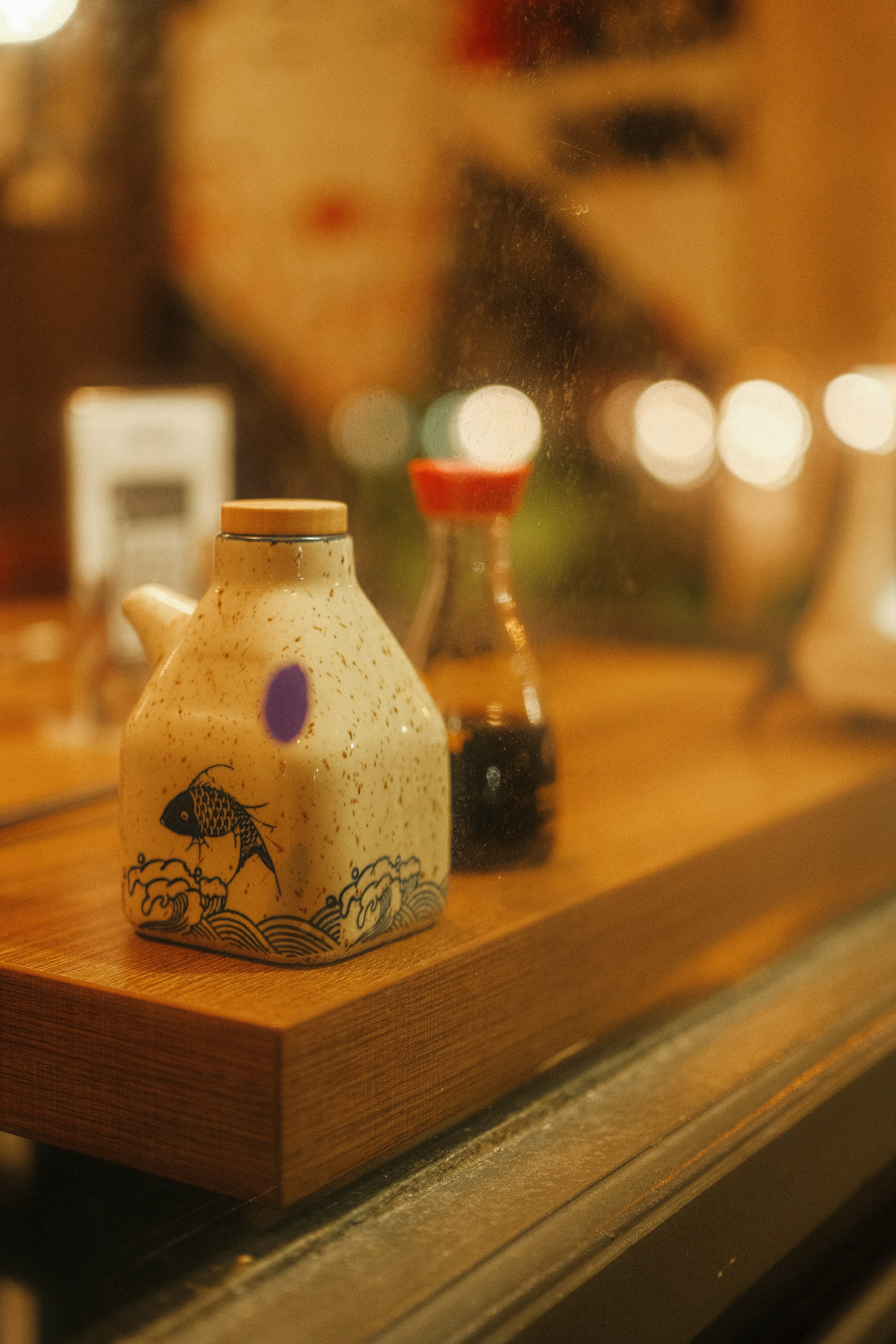 Ceramic Sake Vessel on a Wooden Bar with Soy Bottle Backlit by Neon Glow
